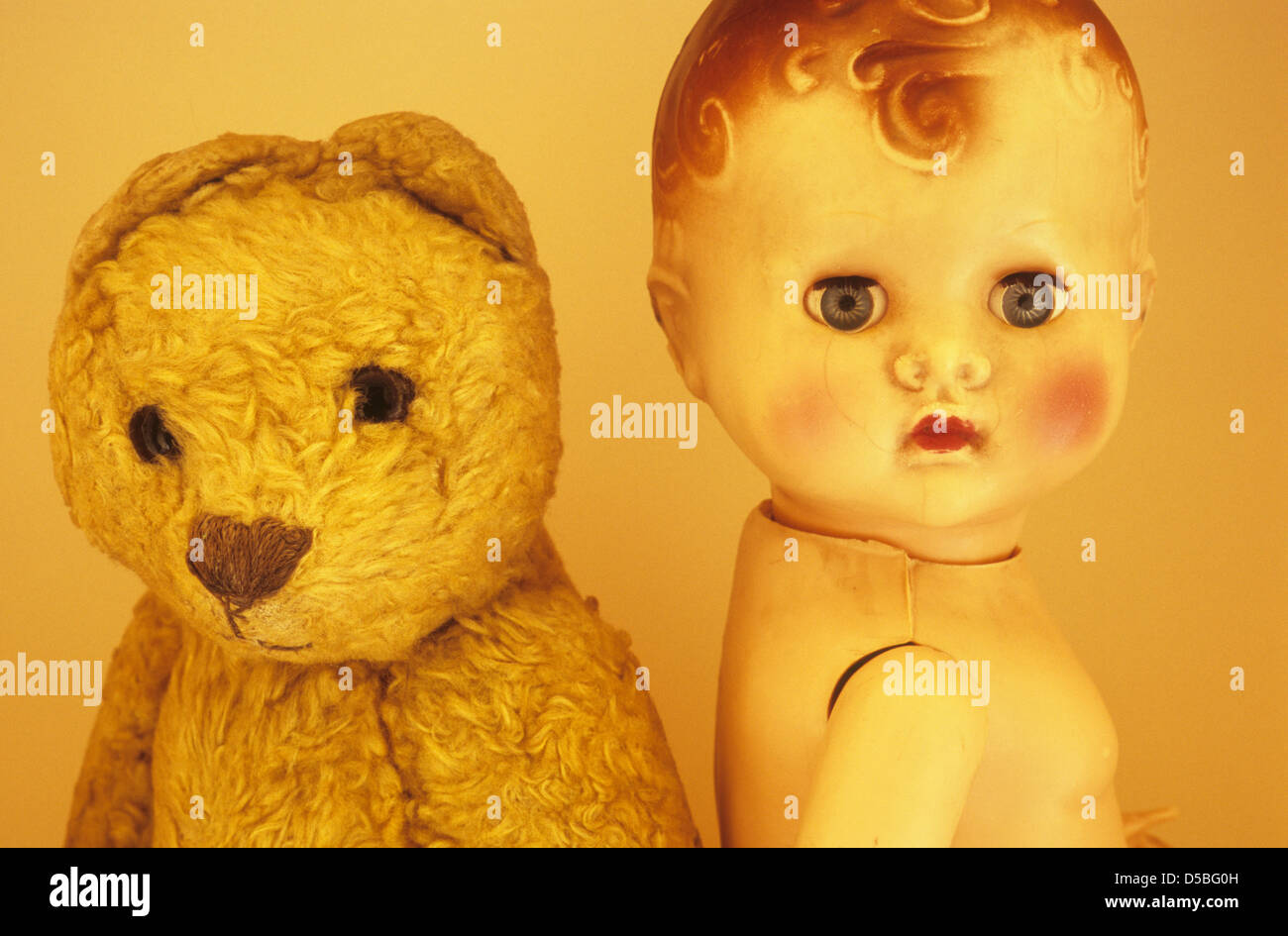 Close up of battered old teddy bear sitting back-to-back with ...