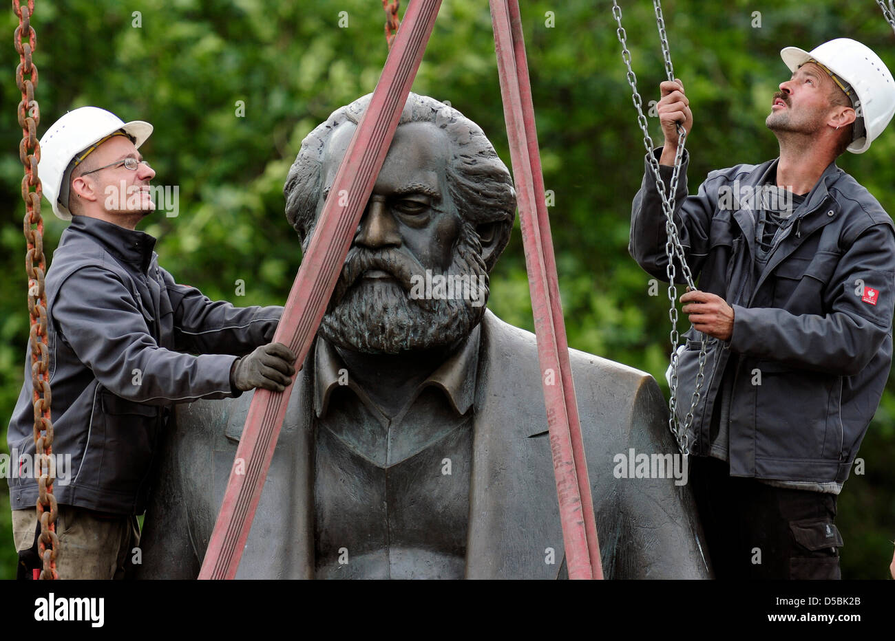 Two workers secure a bronze sculpture of Karl Marx before it is lifted ...