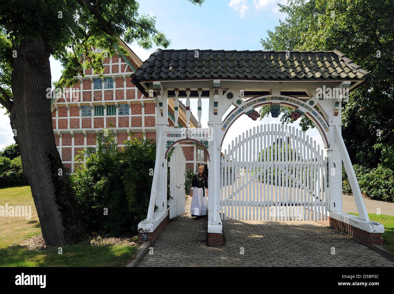 A tour guide in traditional garb poses next to an ornamented gate in ...