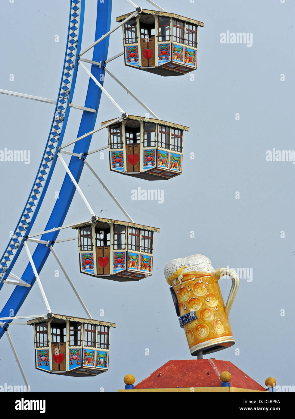 A giant beer mug sits on top of a beer tent in front of a ferris wheel ...