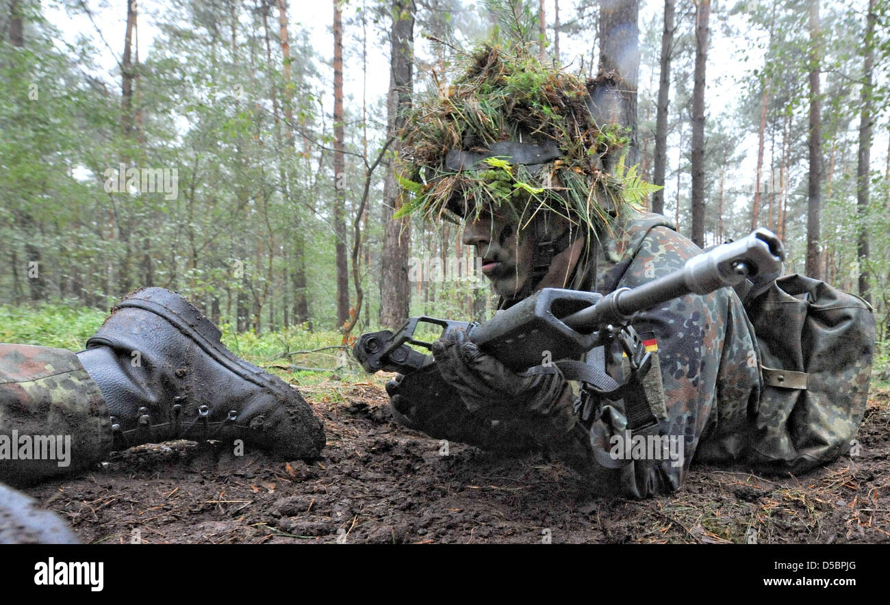 A conscript of German Bundeswehr armed forces crawls through a wood ...