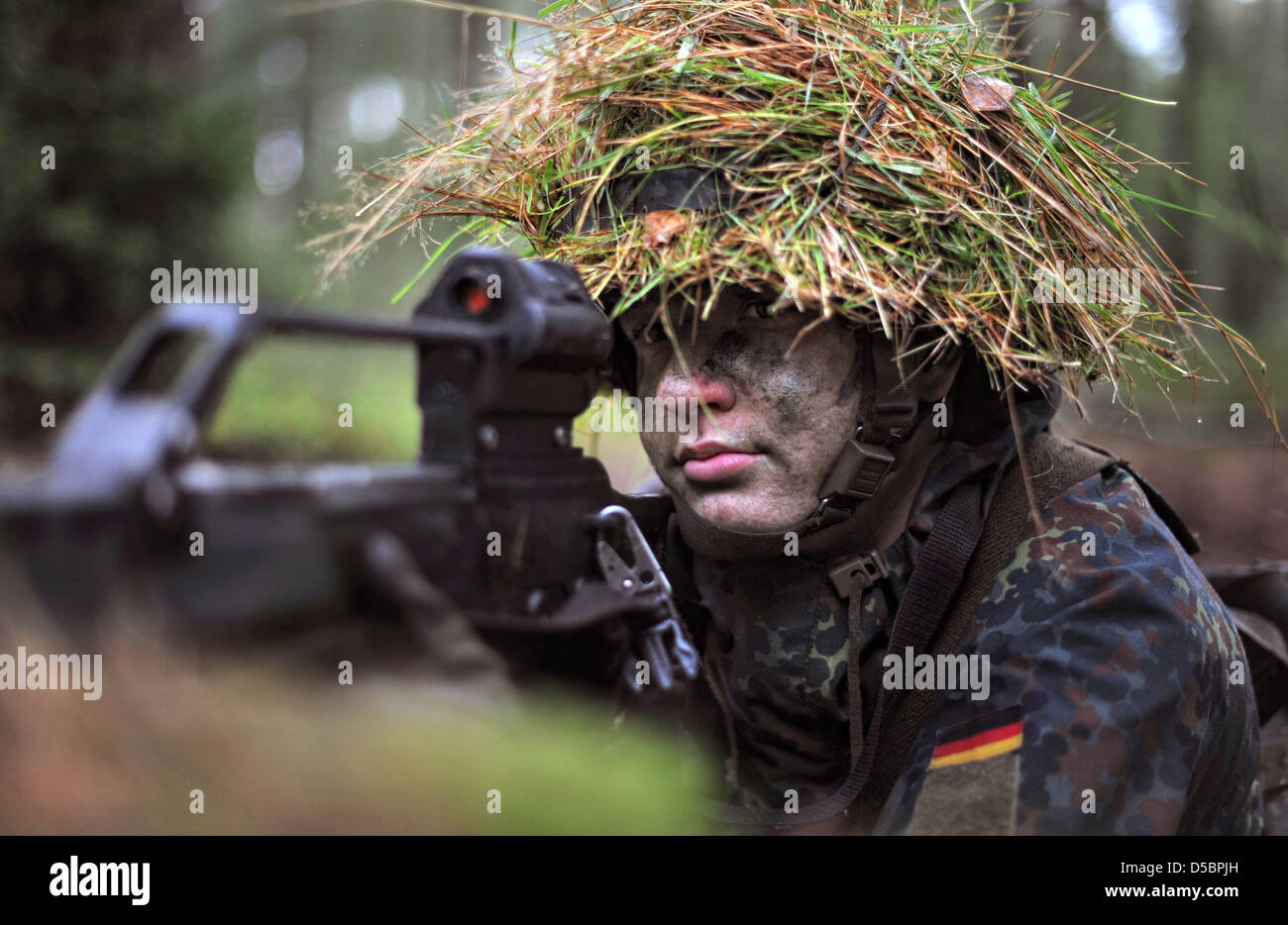 A conscript of German Bundeswehr armed forces crawls through a wood ...
