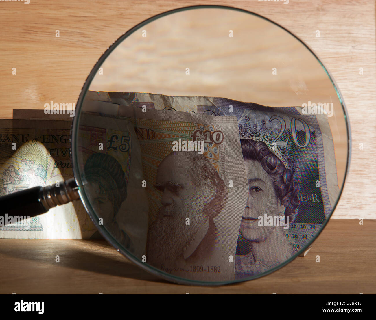 UK banknotes seen through a magnifying glass. Concept of growth or ...