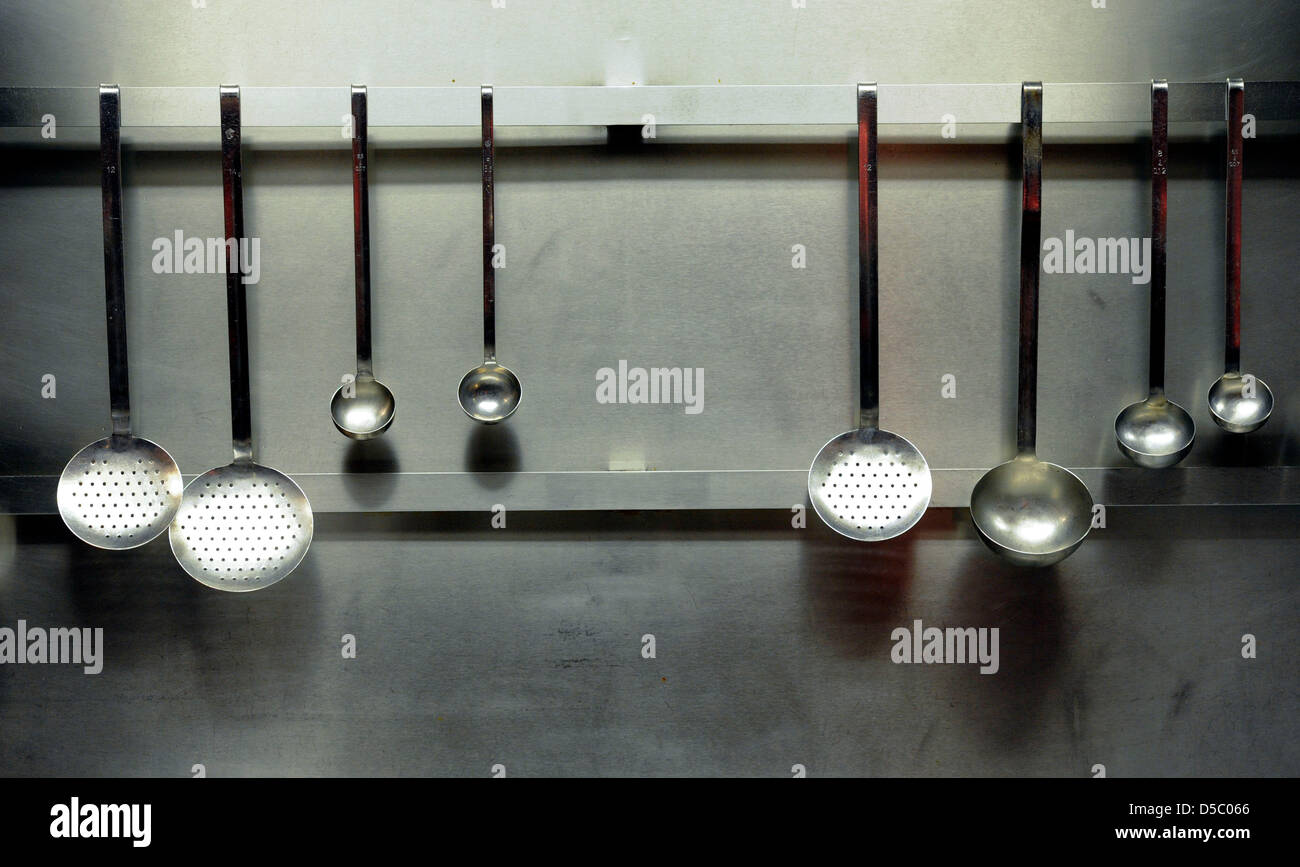 Several ladles hang on the premium steel wall in a vast kitchen in ...