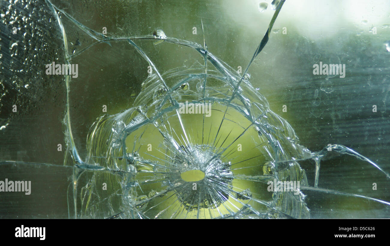 Cracked window bullet hole water damp liquid Stock Photo - Alamy