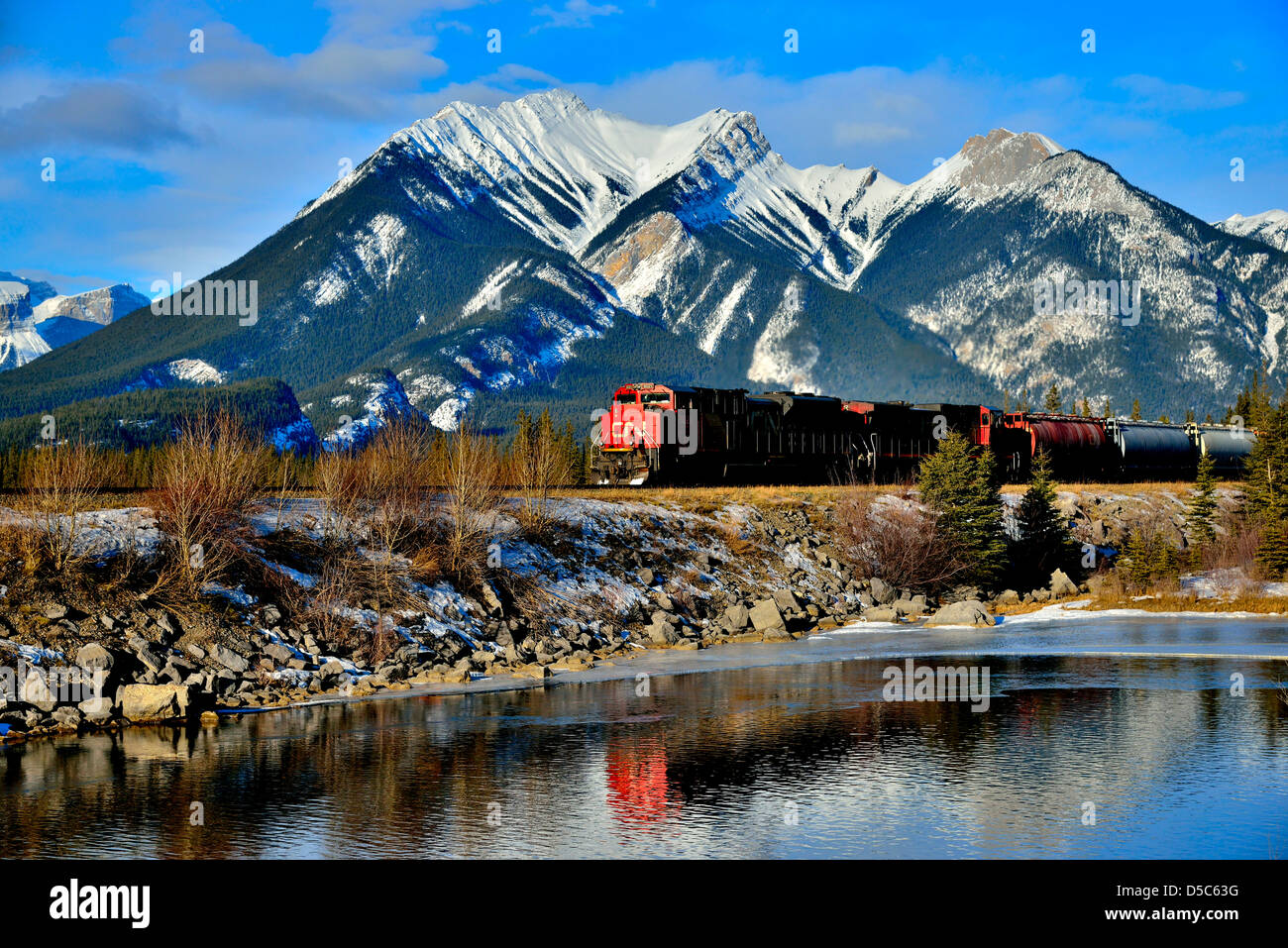 A Canadian National freight train passing a snow-capped rocky mountain ...