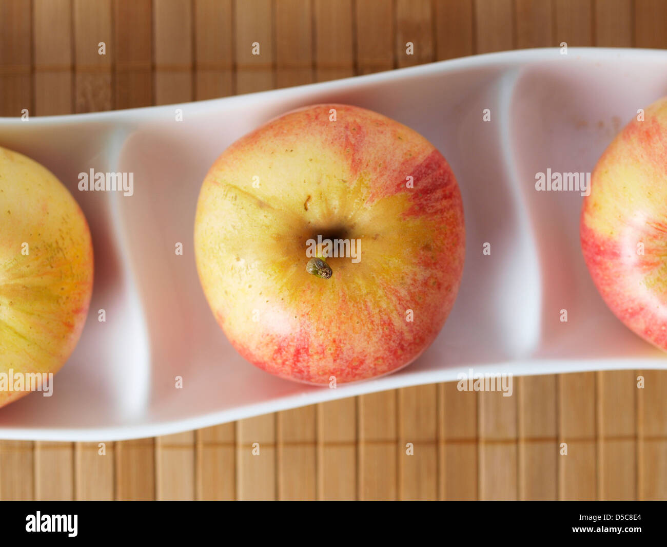Three apples in a white bowl. The photo is taken from an overhead shot ...