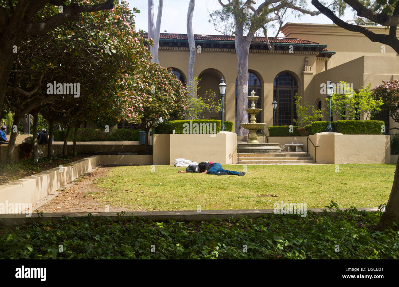 A homeless man asleep on the lawn in front of the Santa Barbara Public ...