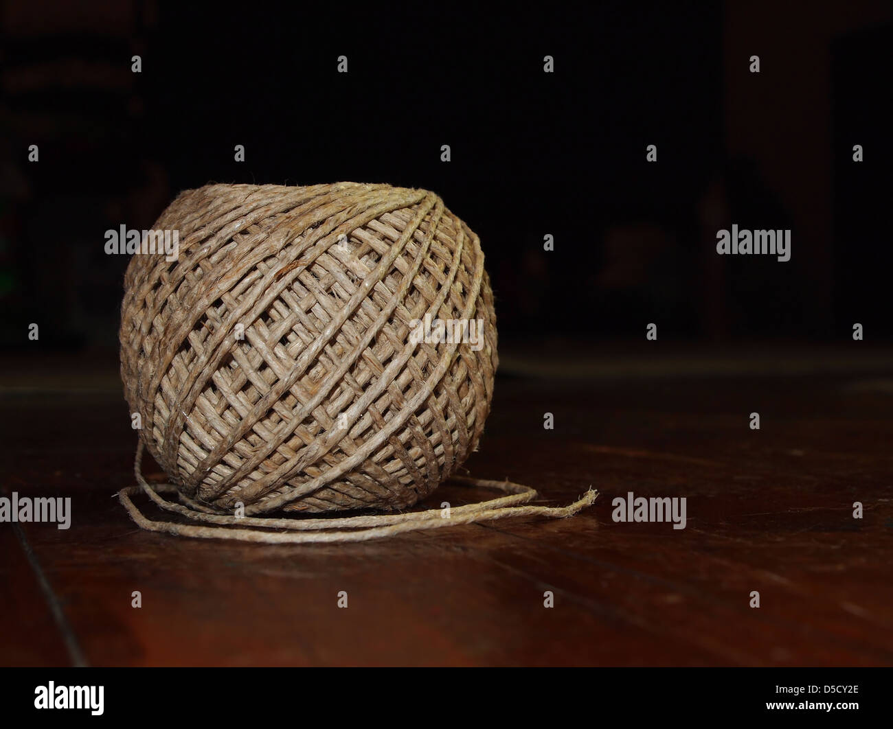 A ball of natural jute twine on a wooden surface in low, ambient lighting Stock Photo - Alamy