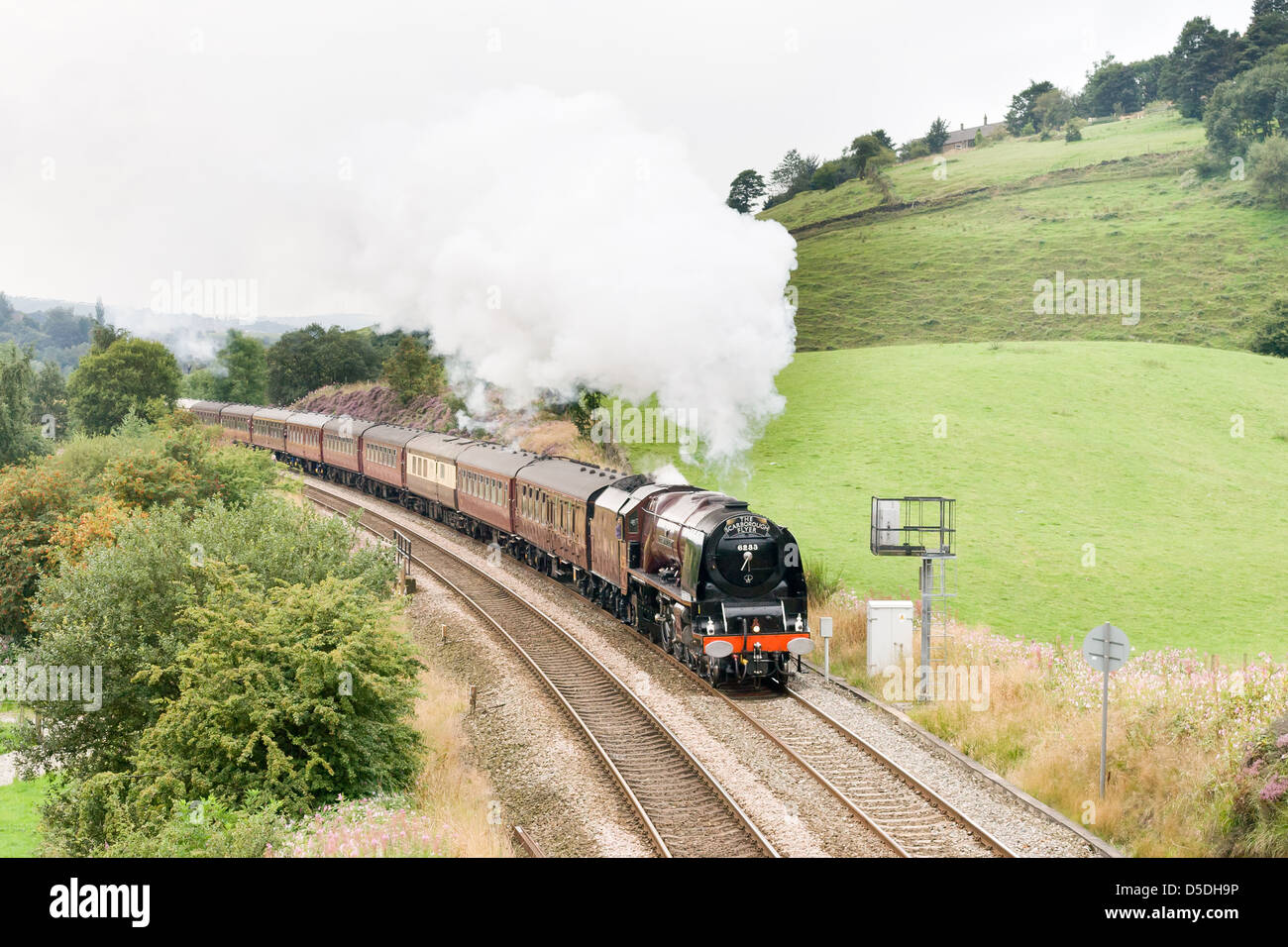 A steam locomotive pulling a passenger train on the main line through ...