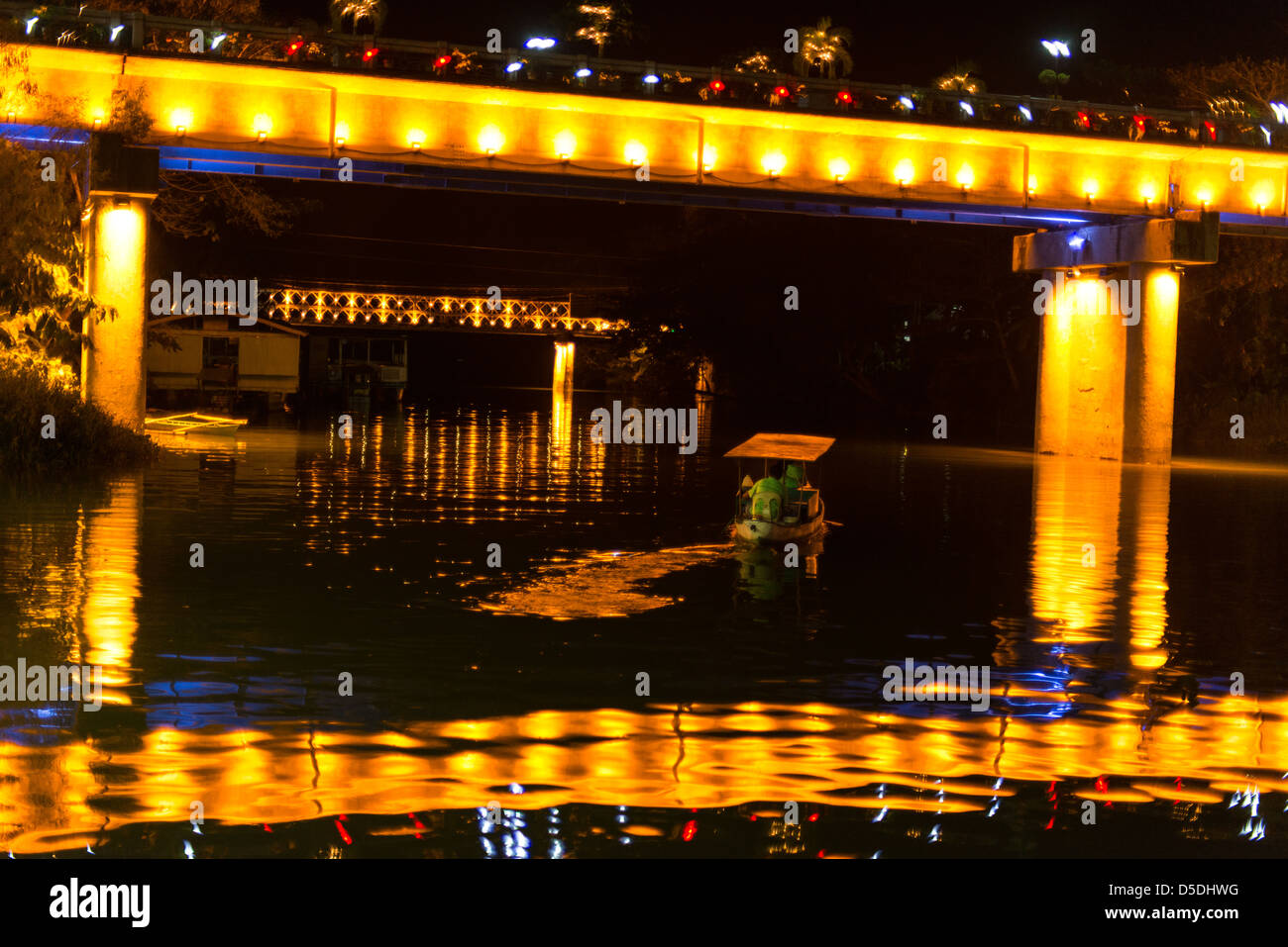 Bridge over Loboc river colorfully lit and casting a reflection in the ...