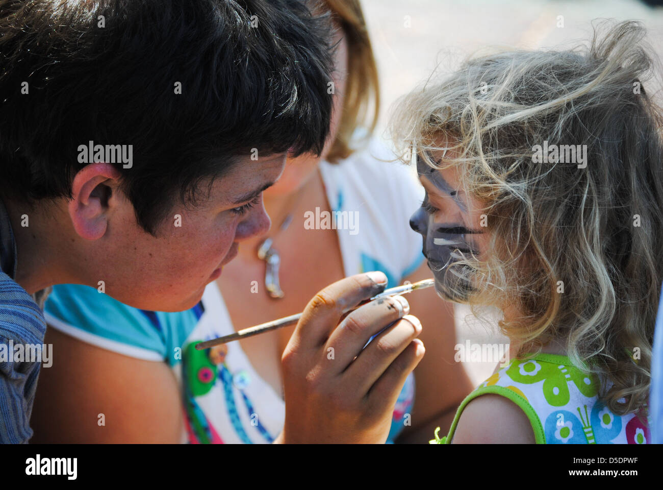 A young girl getting her face painted at a fair Stock Photo - Alamy