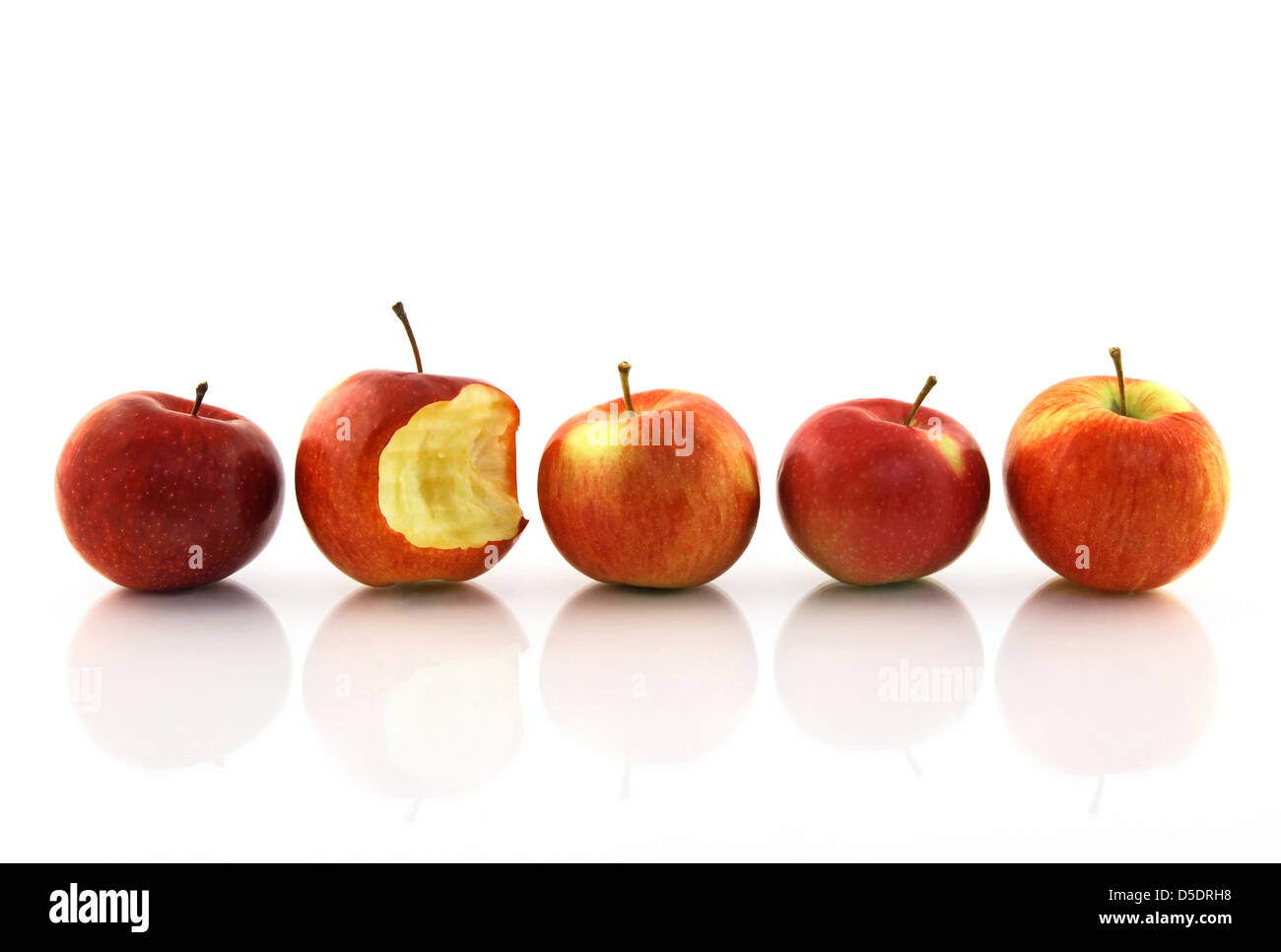 One half-bitten apple among the whole red apples, reflecting on white ...