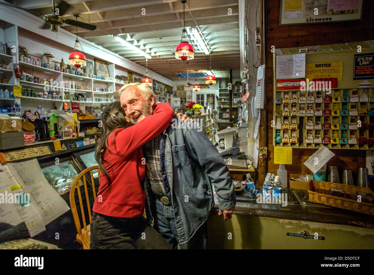 The proprietor of an old fashioned general store hugs an old customer ...