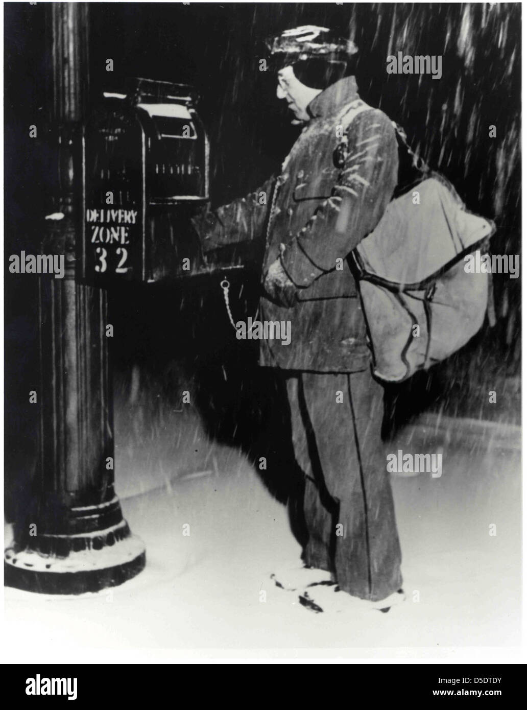 This photograph shows a letter carrier delivering mail in snowy ...