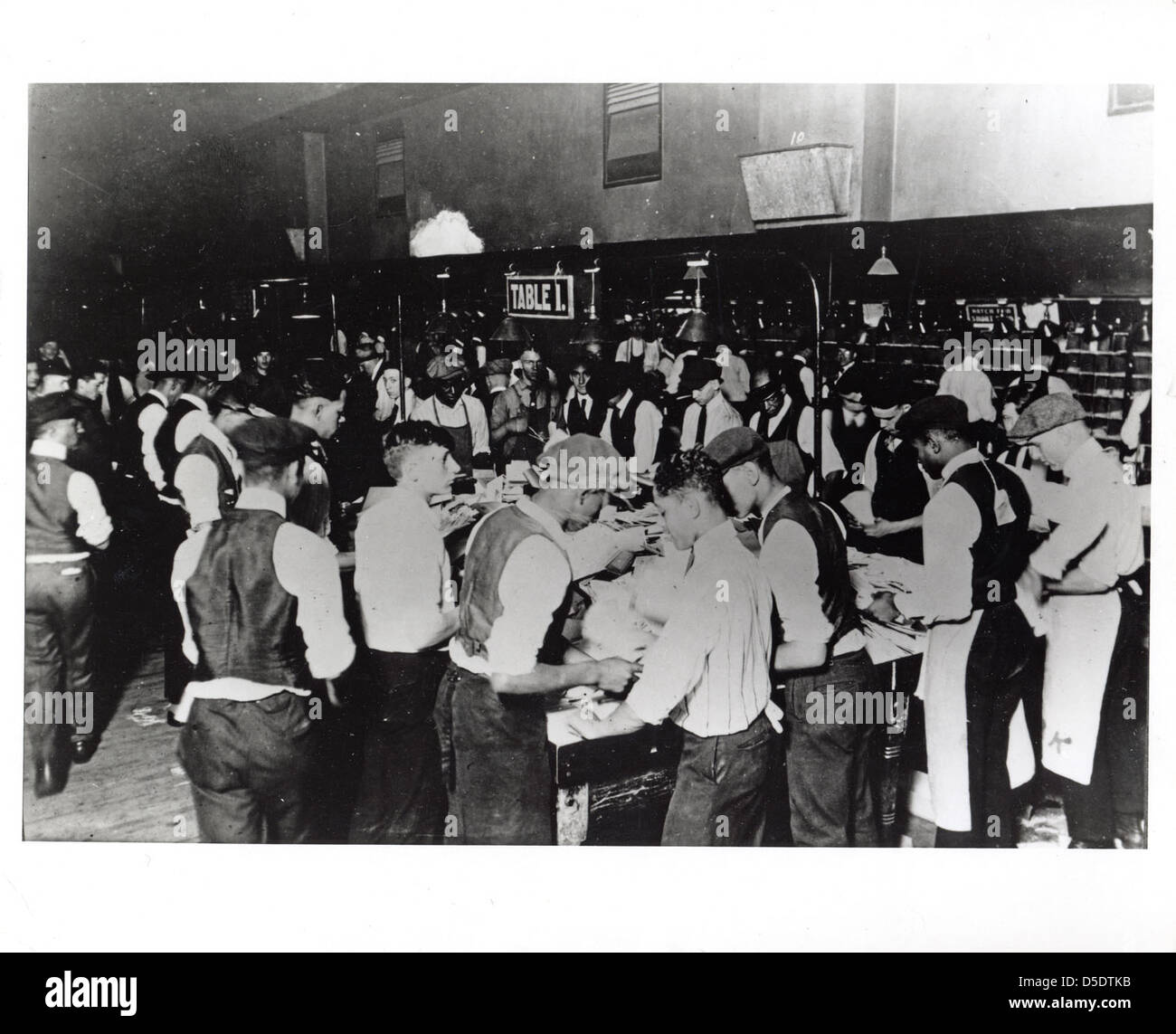 A 1930 photograph showing postal clerks sorting mail in a busy post ...