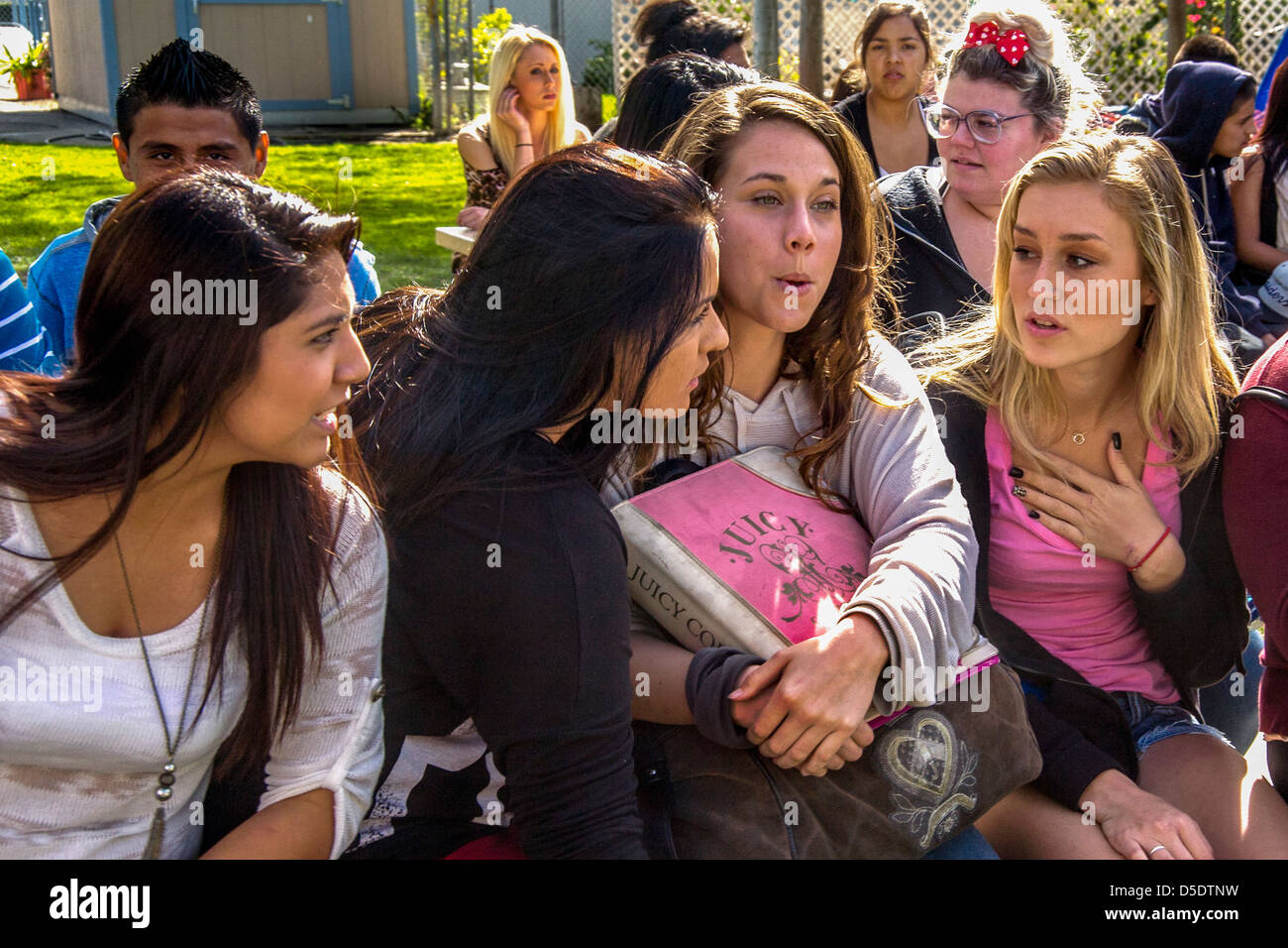 Hispanic and Caucasian high school girls share a secret on campus in ...
