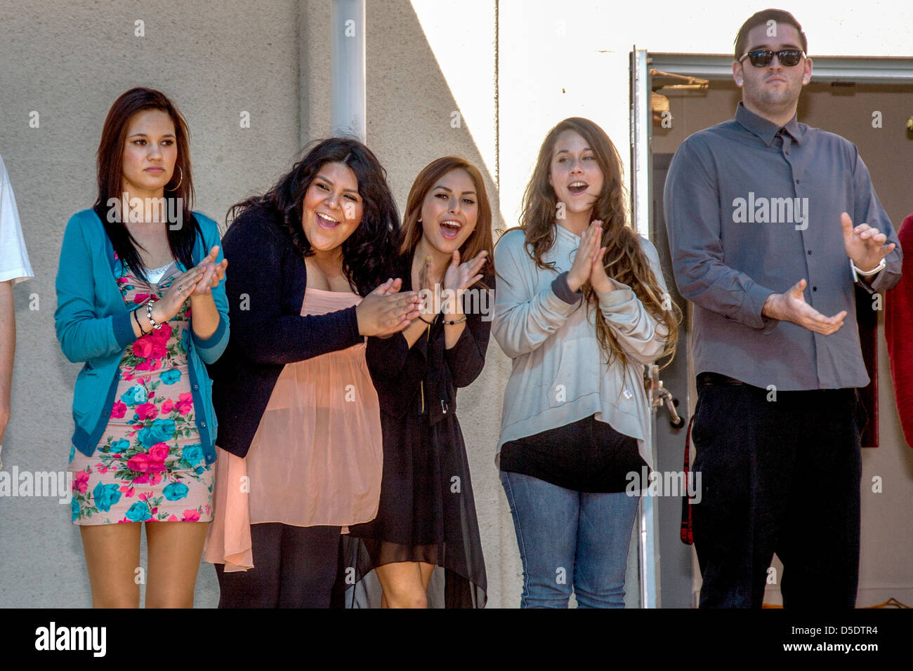 Casually dressed students cheer their classmates on graduation day at a ...