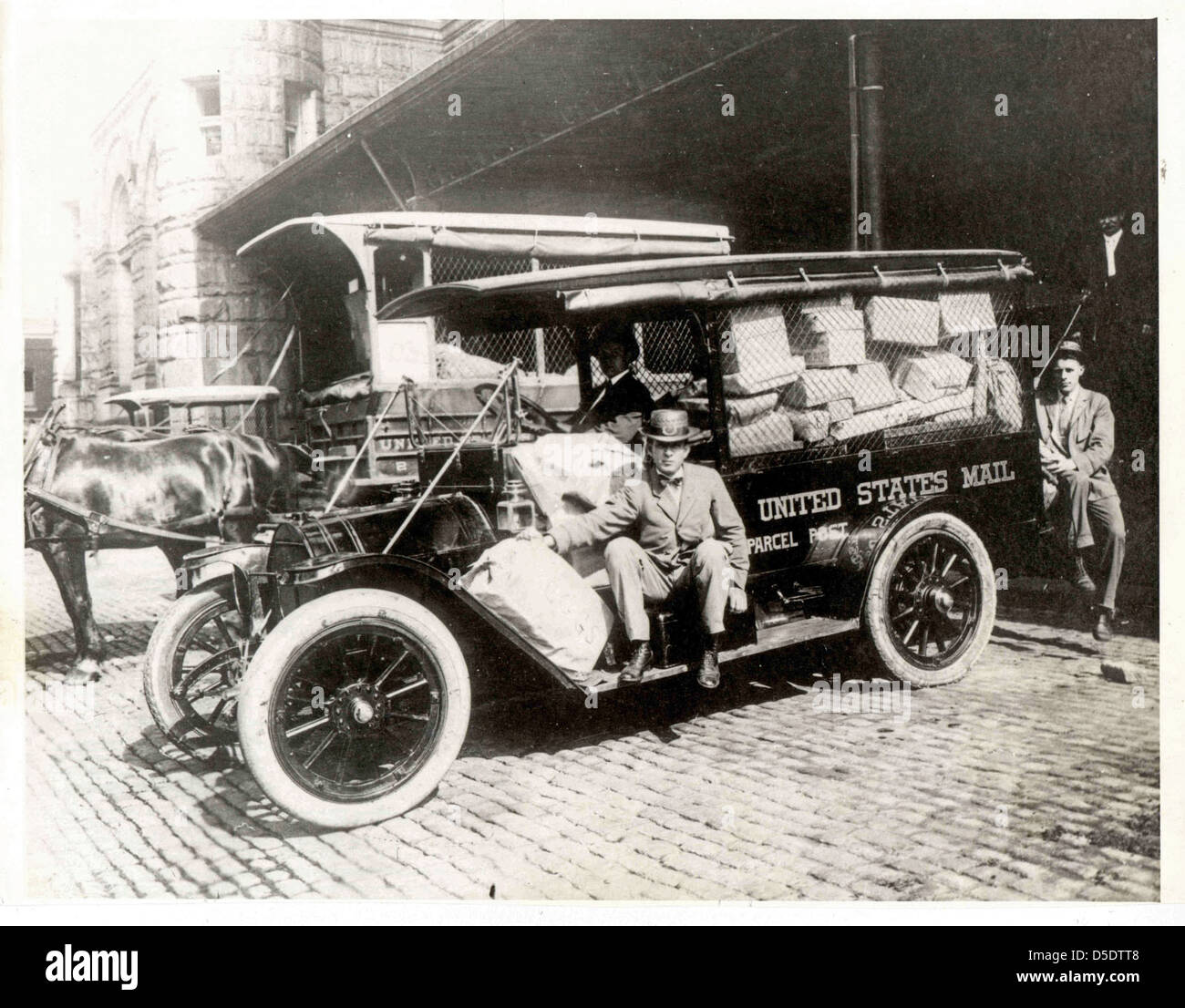 A historic photograph showing early parcel post vehicles and employees ...