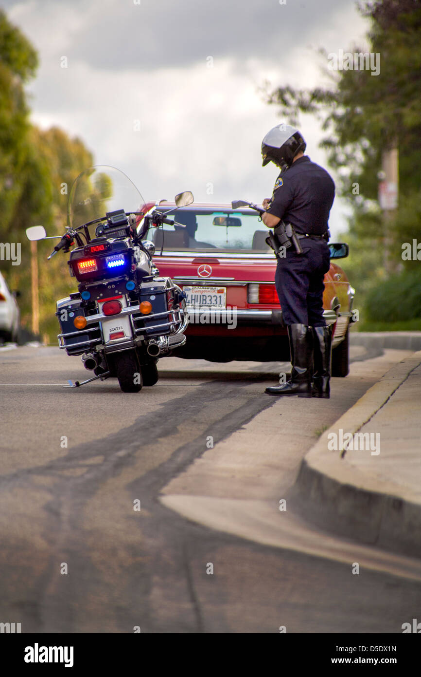 A motorcycle policeman writes a ticket at a traffic stop in Orange, CA ...