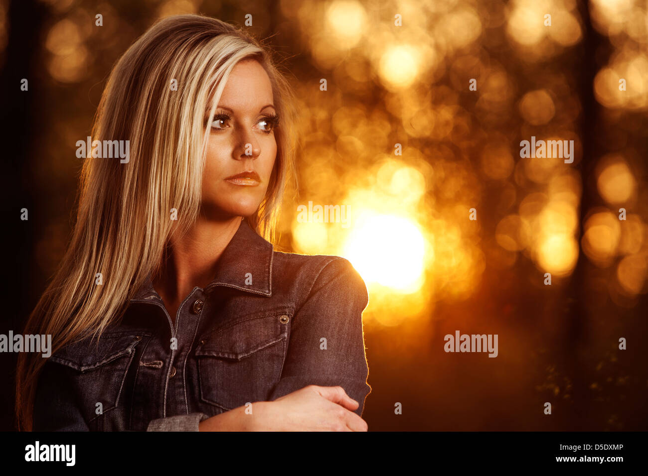 Woman standing outside in front of setting sun Stock Photo - Alamy