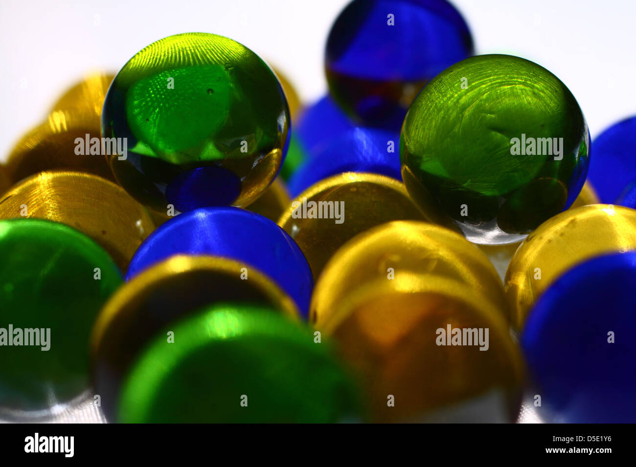 Blue yellow and green marbles on a white background Stock Photo - Alamy