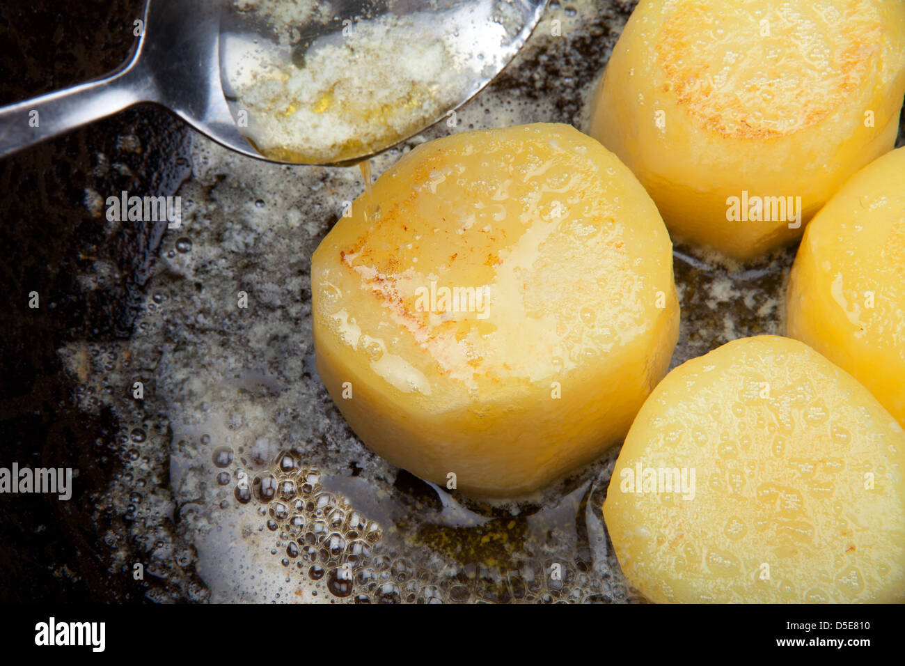 fondant potato frying in sauce pan. butter basting food with spoon ...