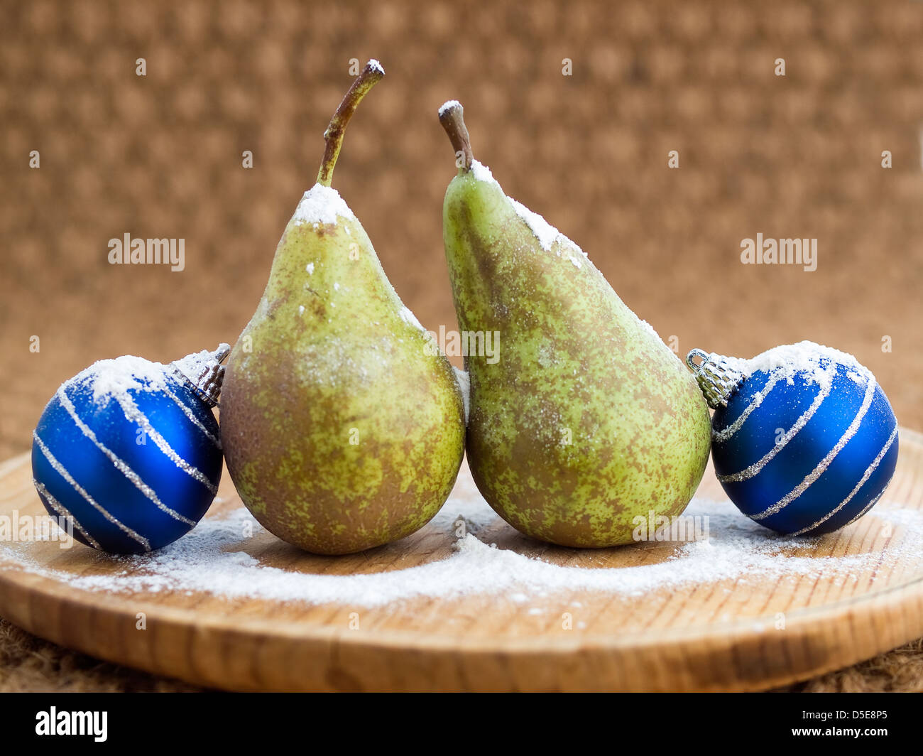 Two pears and two Christmas balls with flour imitation snow on a wooden ...