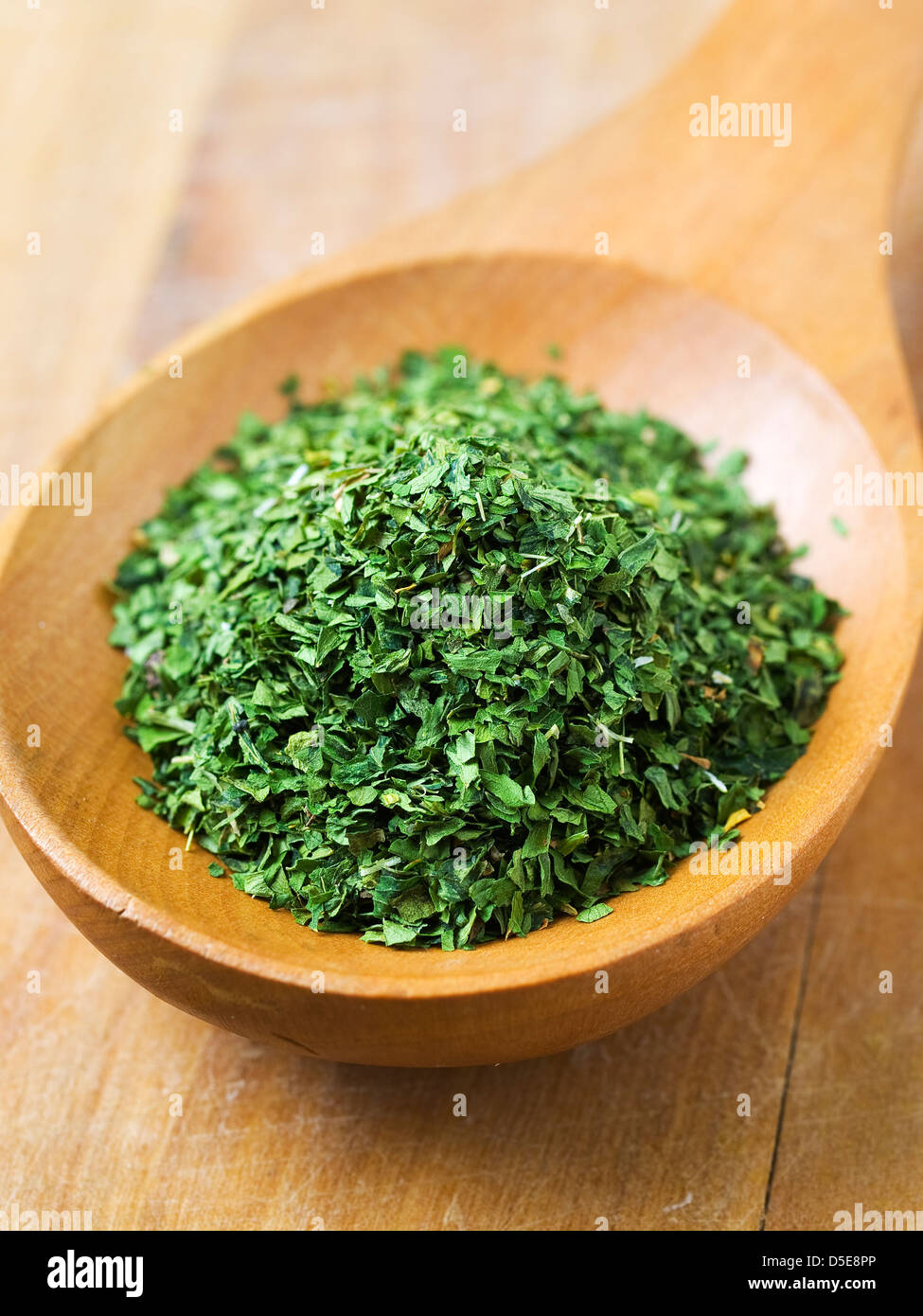 Parsley seasoning in a wooden spoon. Vertical composition Stock Photo ...