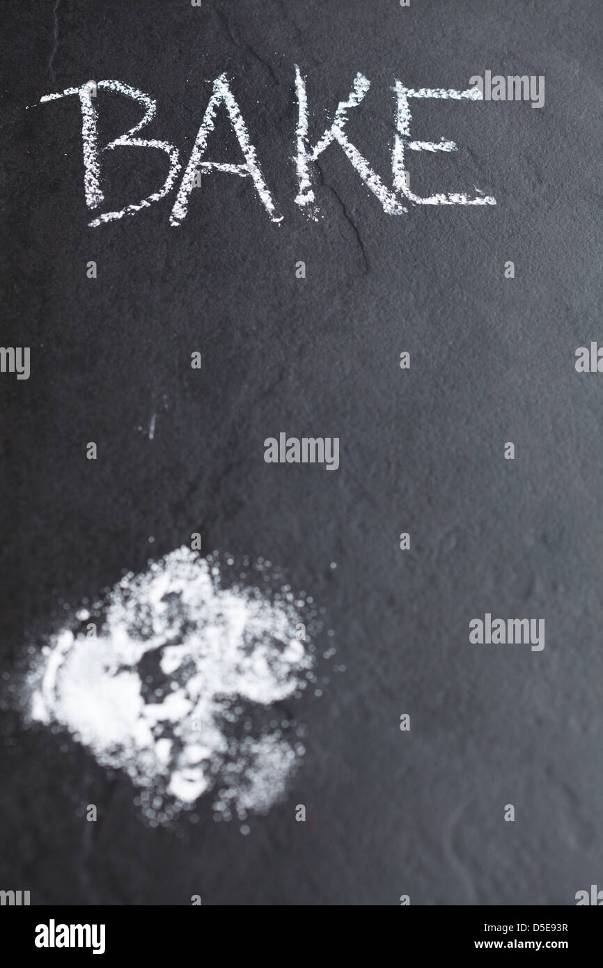 Closeup of dark background with icing sugar and word bake written in ...