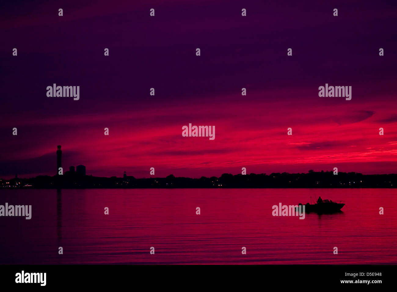 A pink and purple sunset reflecting off the sea with a small fishing ...