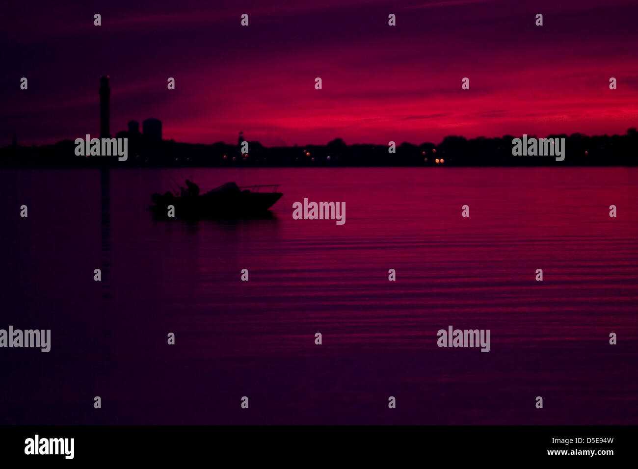 A pink and purple sunset reflecting off the sea with a small fishing ...