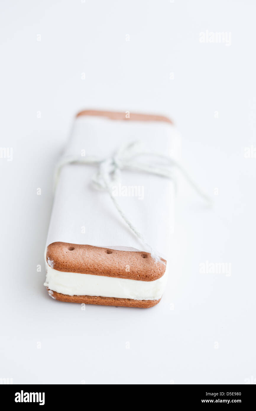 Closeup of vanilla ice cream biscuit wrapped in white paper with string ...