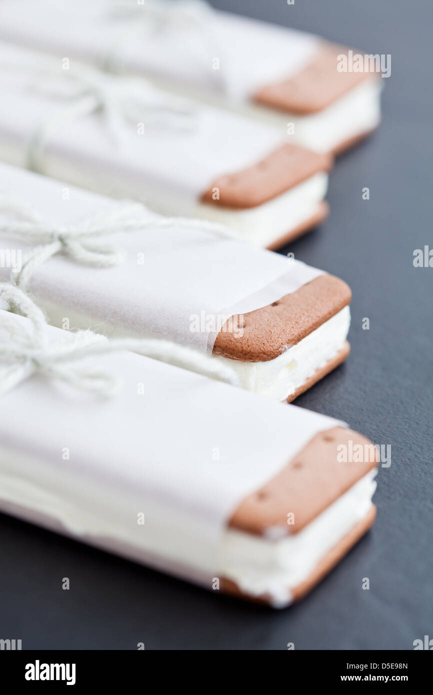 Closeup of row of vanilla ice cream biscuits wrapped in white paper ...
