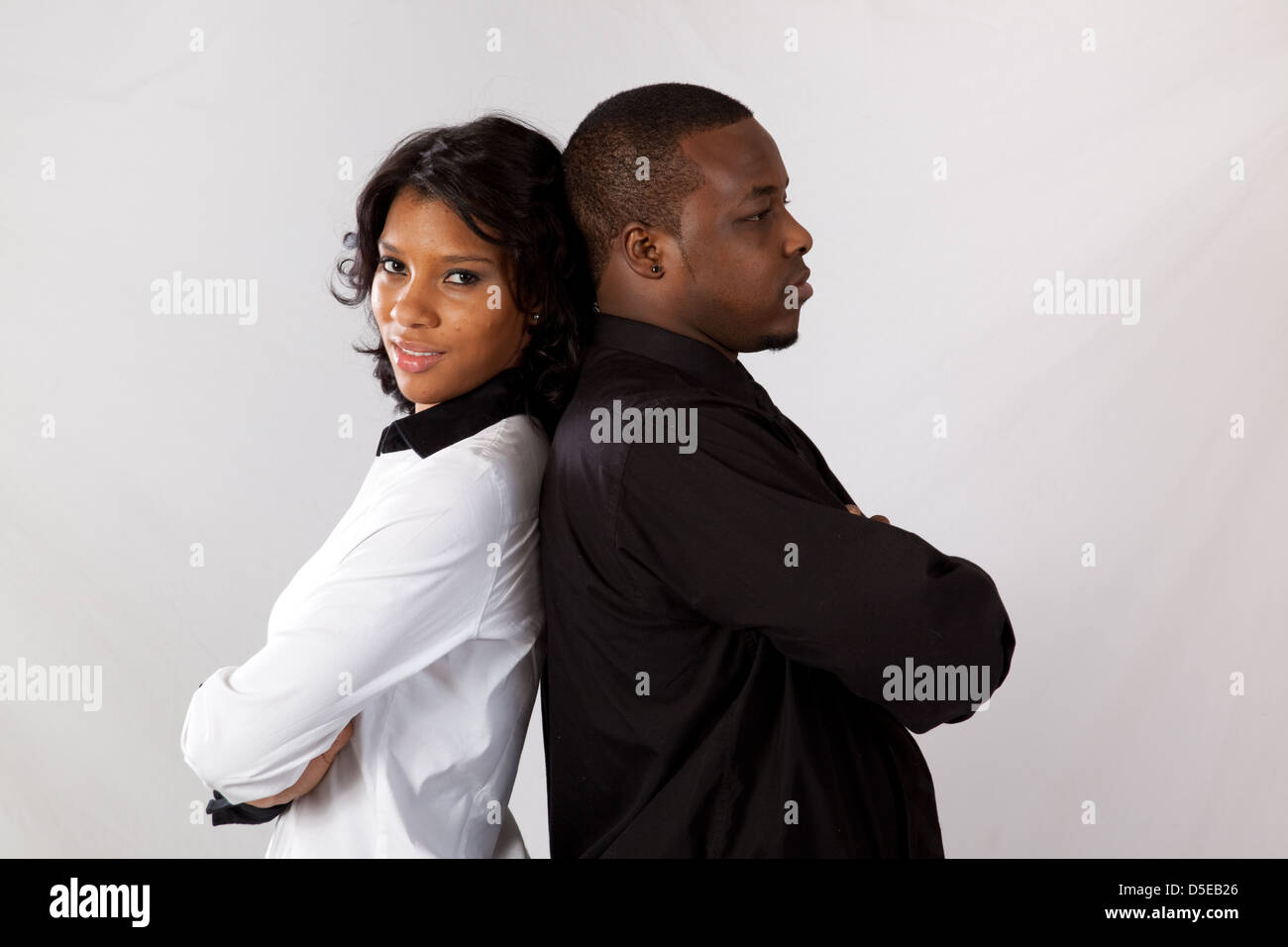 Cute black couple standing back to back with their arms crossed. They ...