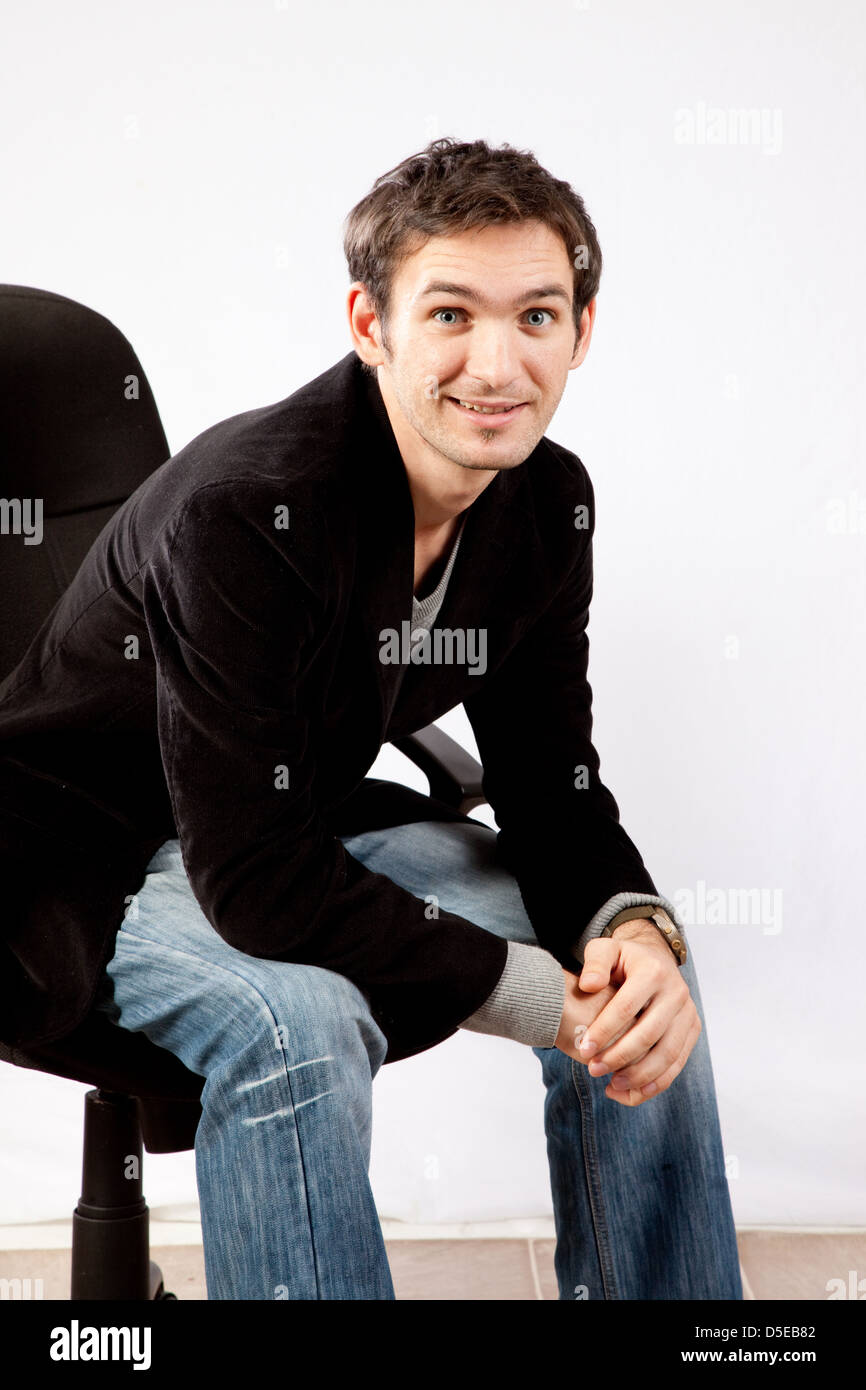 Handsome white man in business suit and blue jeans, sitting with his ...