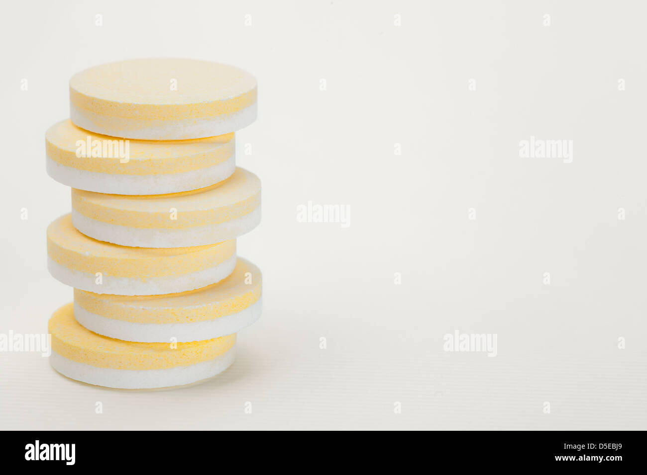 stack of yellow and white tablets on white background with empty space ...