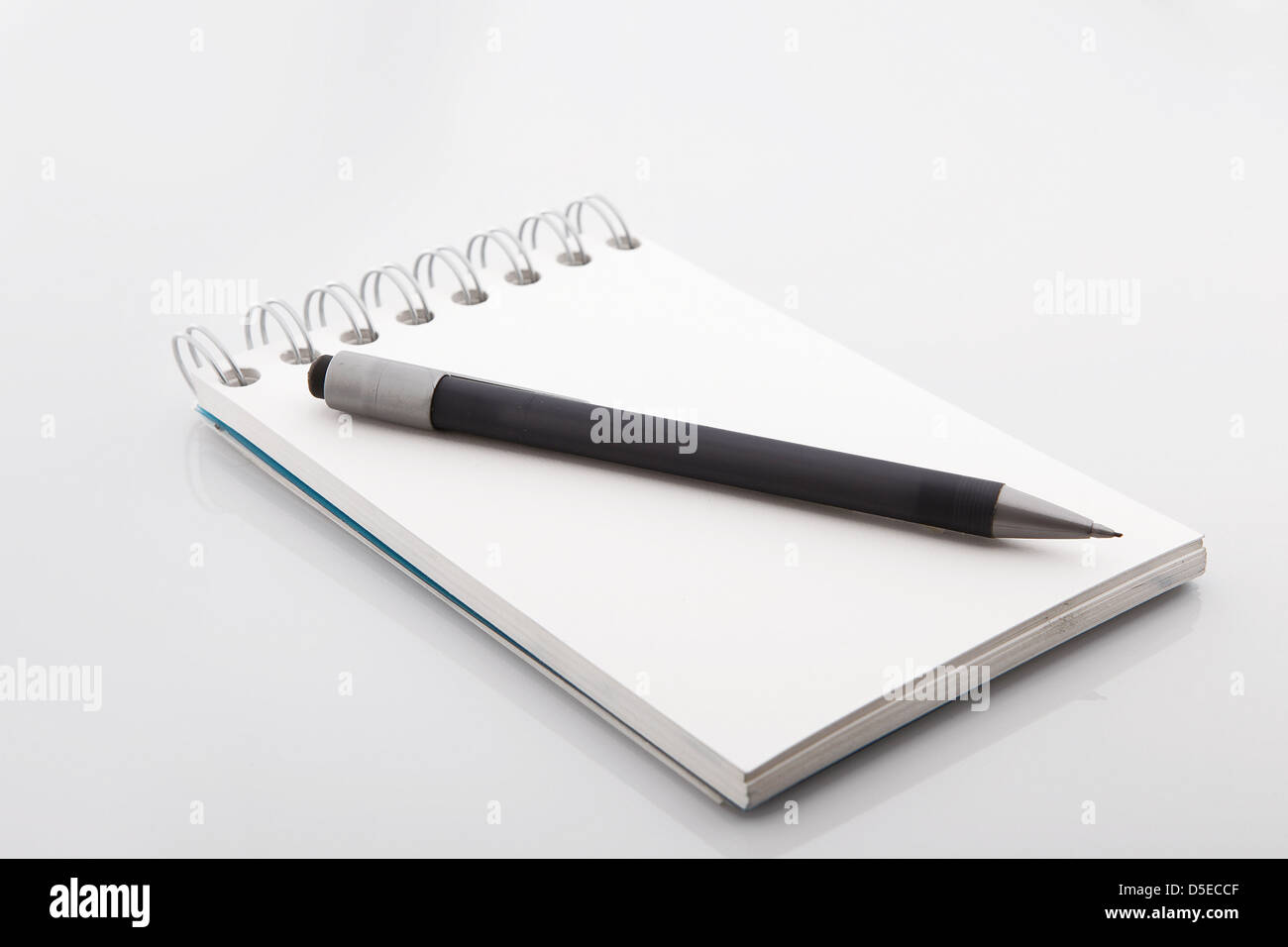 white blocknote , with a pencil on it , shot on a white plexi ...