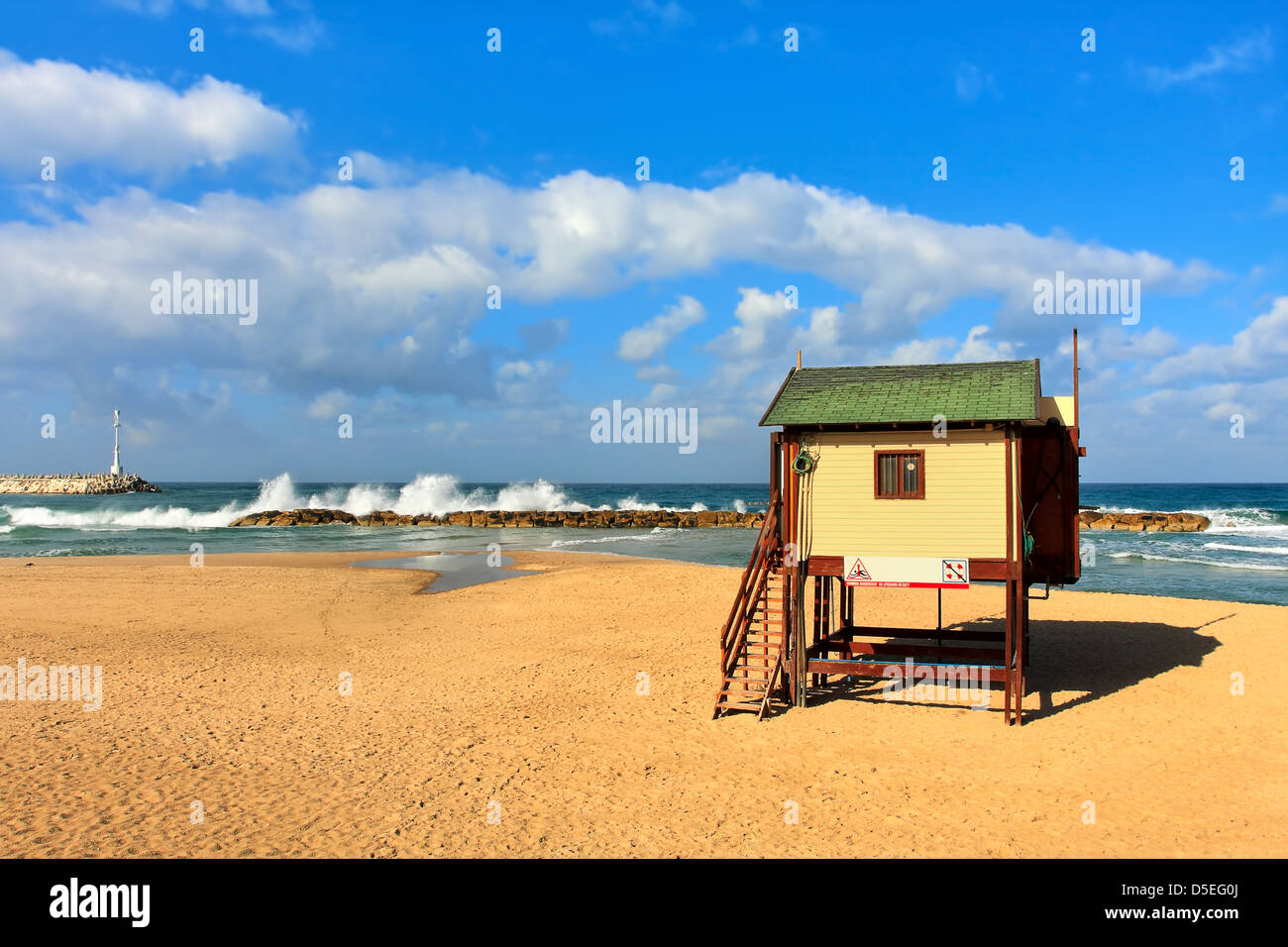 Wooden lifeguard station on empty beach under blue sky with white ...