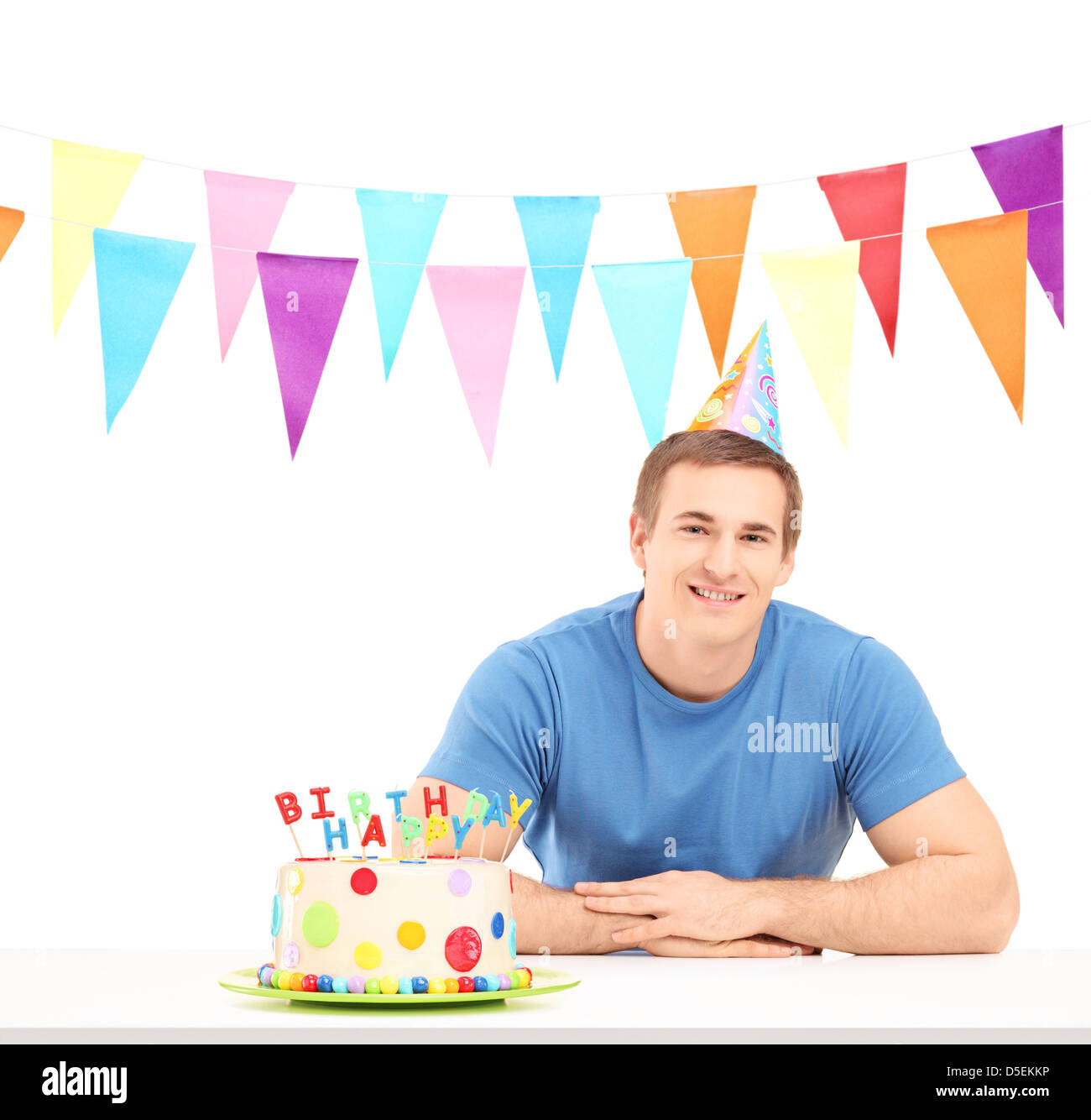 Smiling birthday guy with a party hat and a cake, isolated on white ...