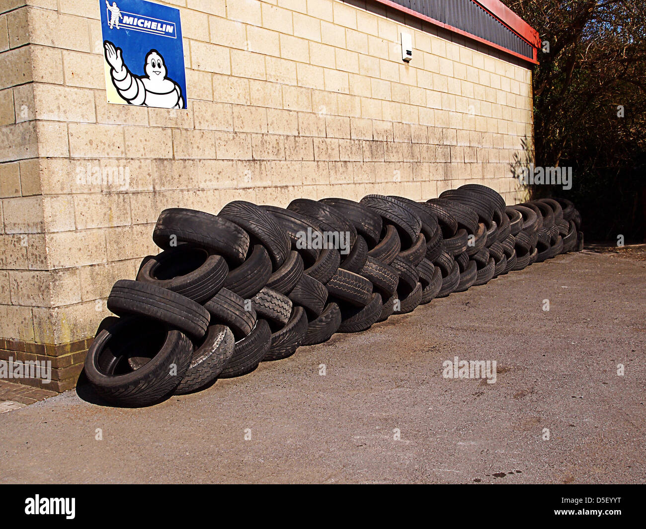 Stack of old and worn tyres outside a small rural garage, in Cheddar ...