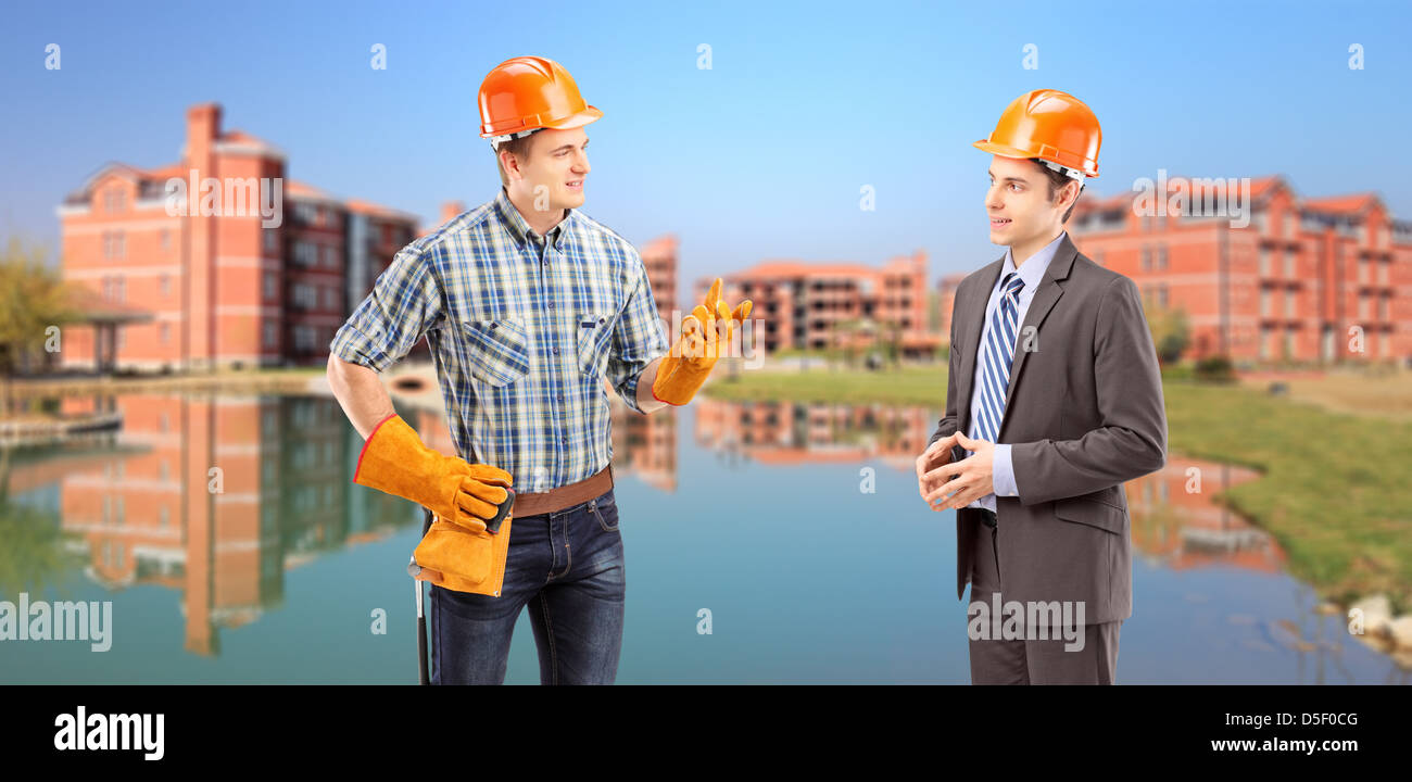 Male manual worker having a conversation with architect, buildings in ...