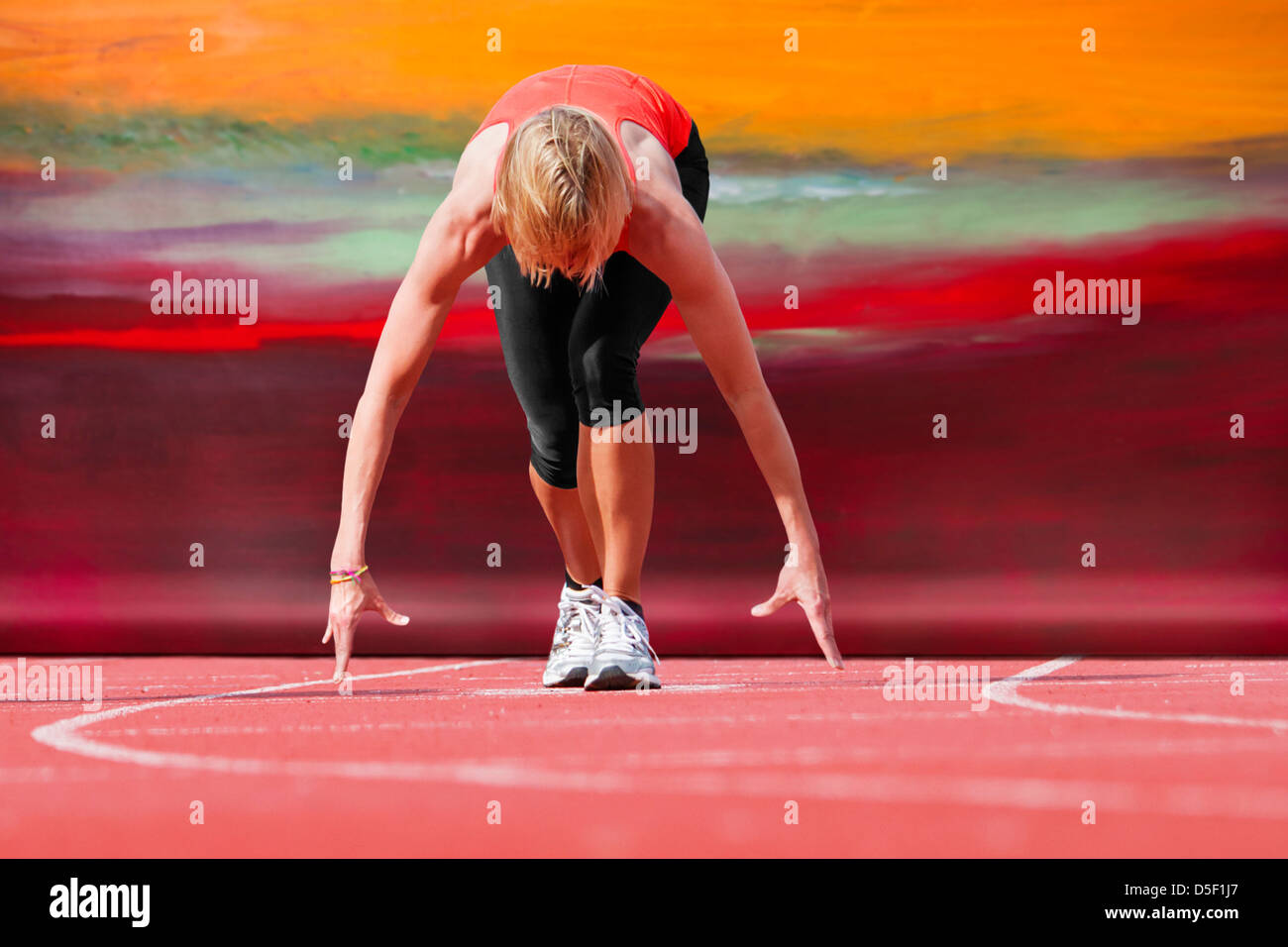 Female runner in start position with canvas in the background Stock ...