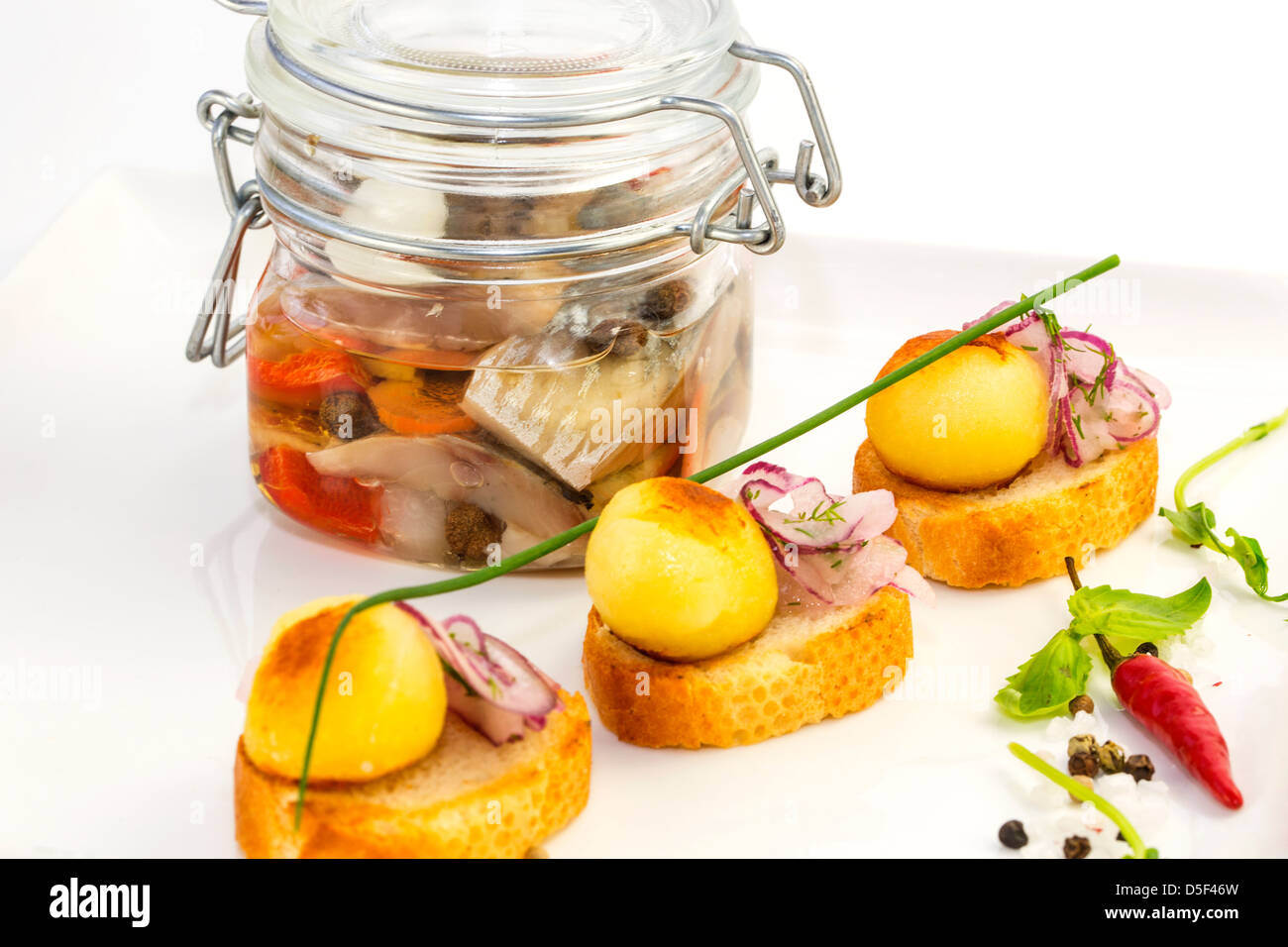 pickled herring in a glass jar with potato canapes Stock Photo - Alamy