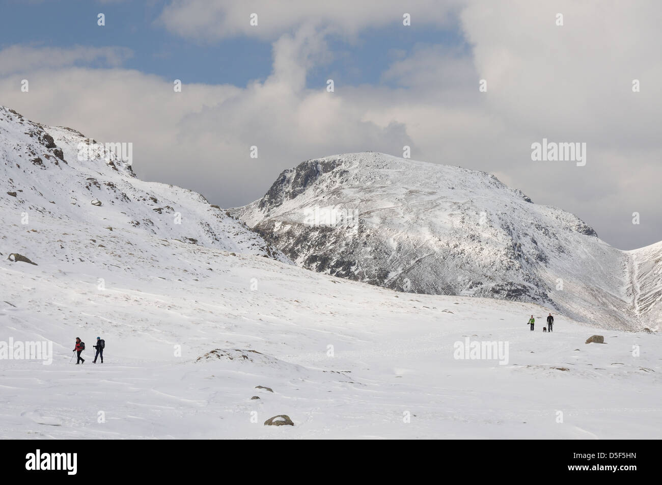 Walkers in winter next to Sprinkling Tarn, with Great Gable in the ...