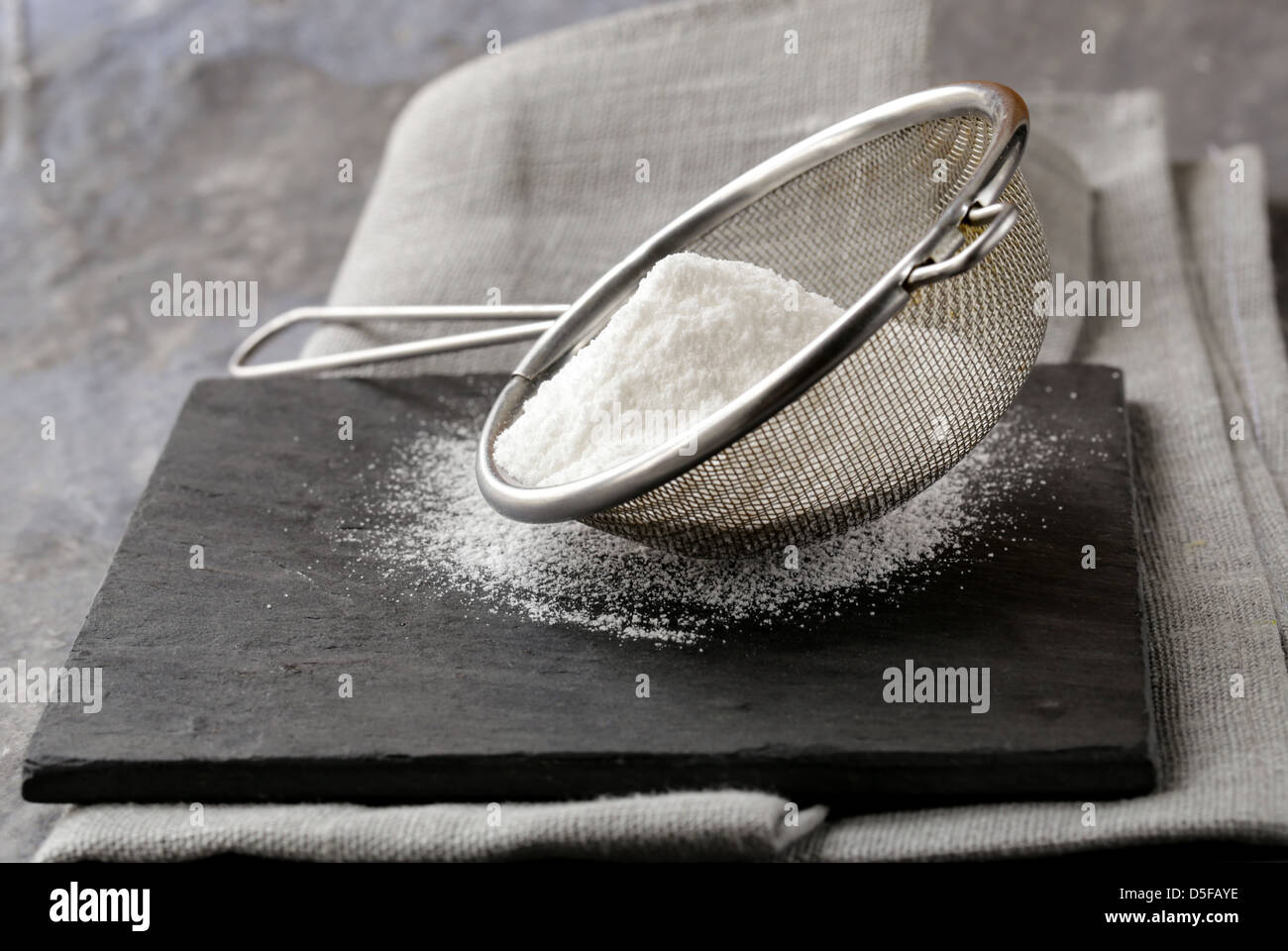 powdered sugar in a metal strainer on a gray background Stock Photo - Alamy