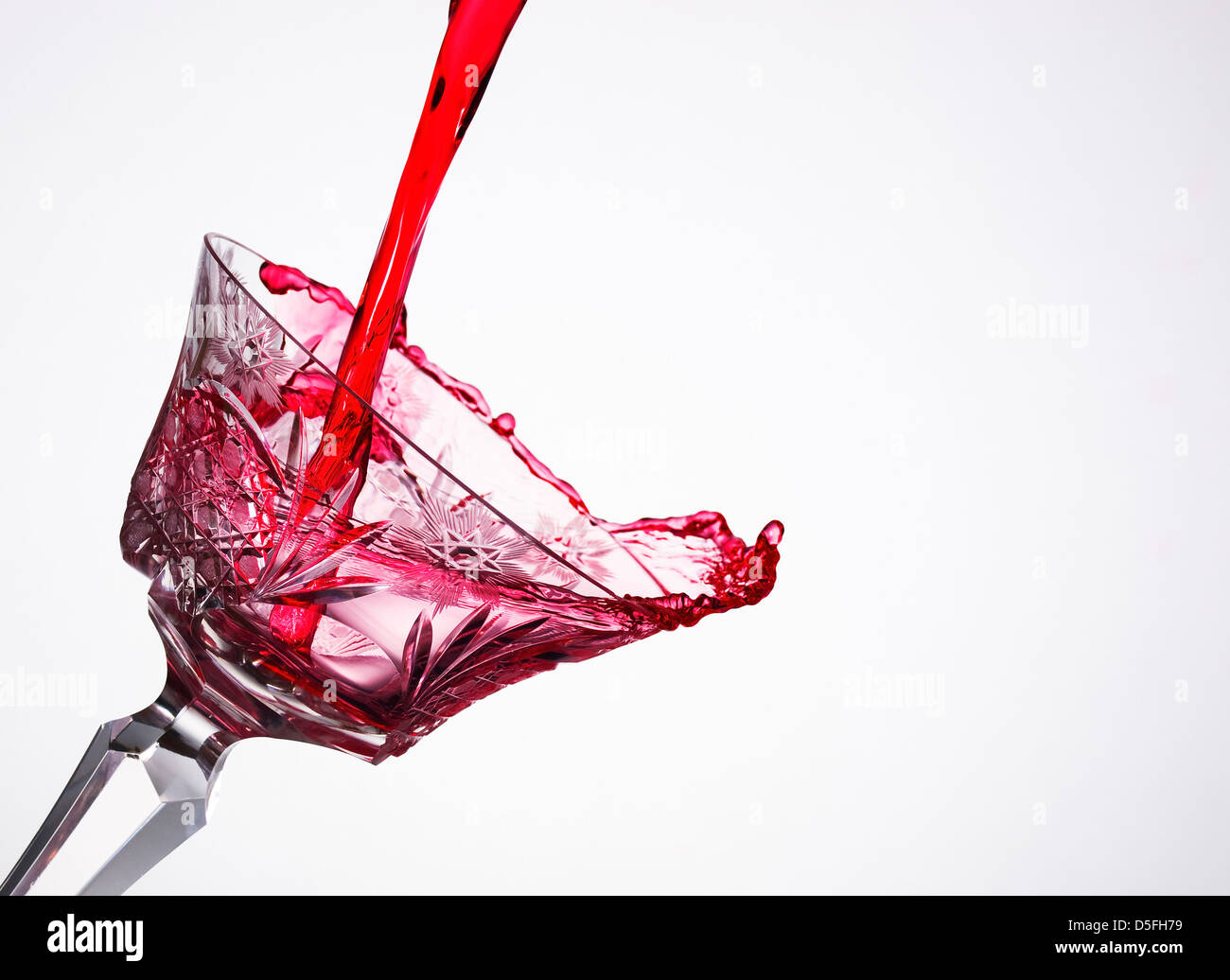 Wine pouring into a glass in diagonal composition and white background ...