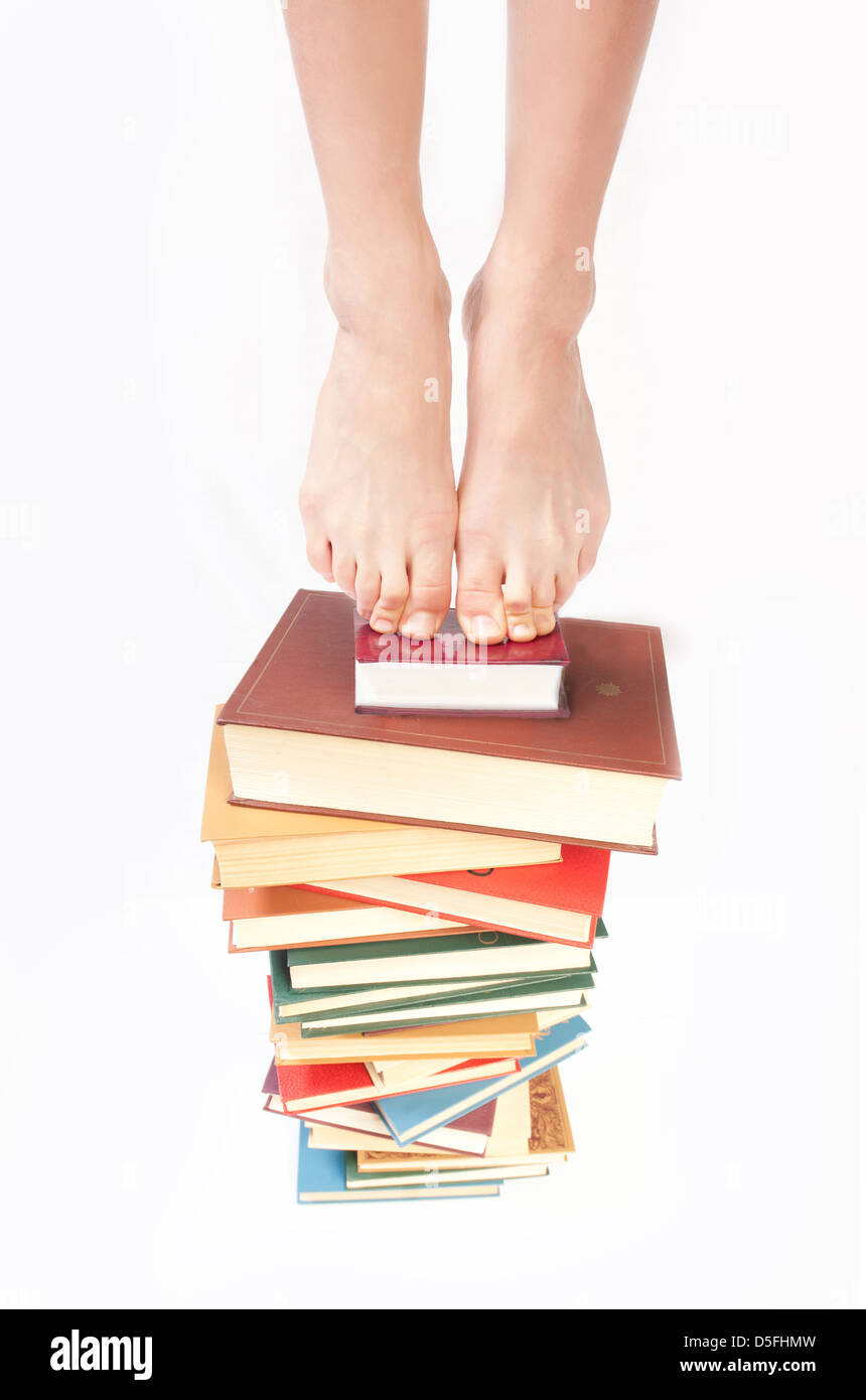 Person standing on a stack of books Stock Photo - Alamy