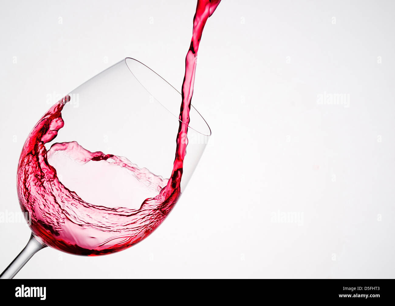 Wine pouring into a glass in diagonal composition and white background ...