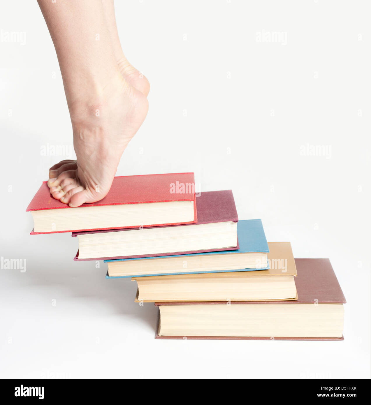 Person standing on a stack of books Stock Photo - Alamy